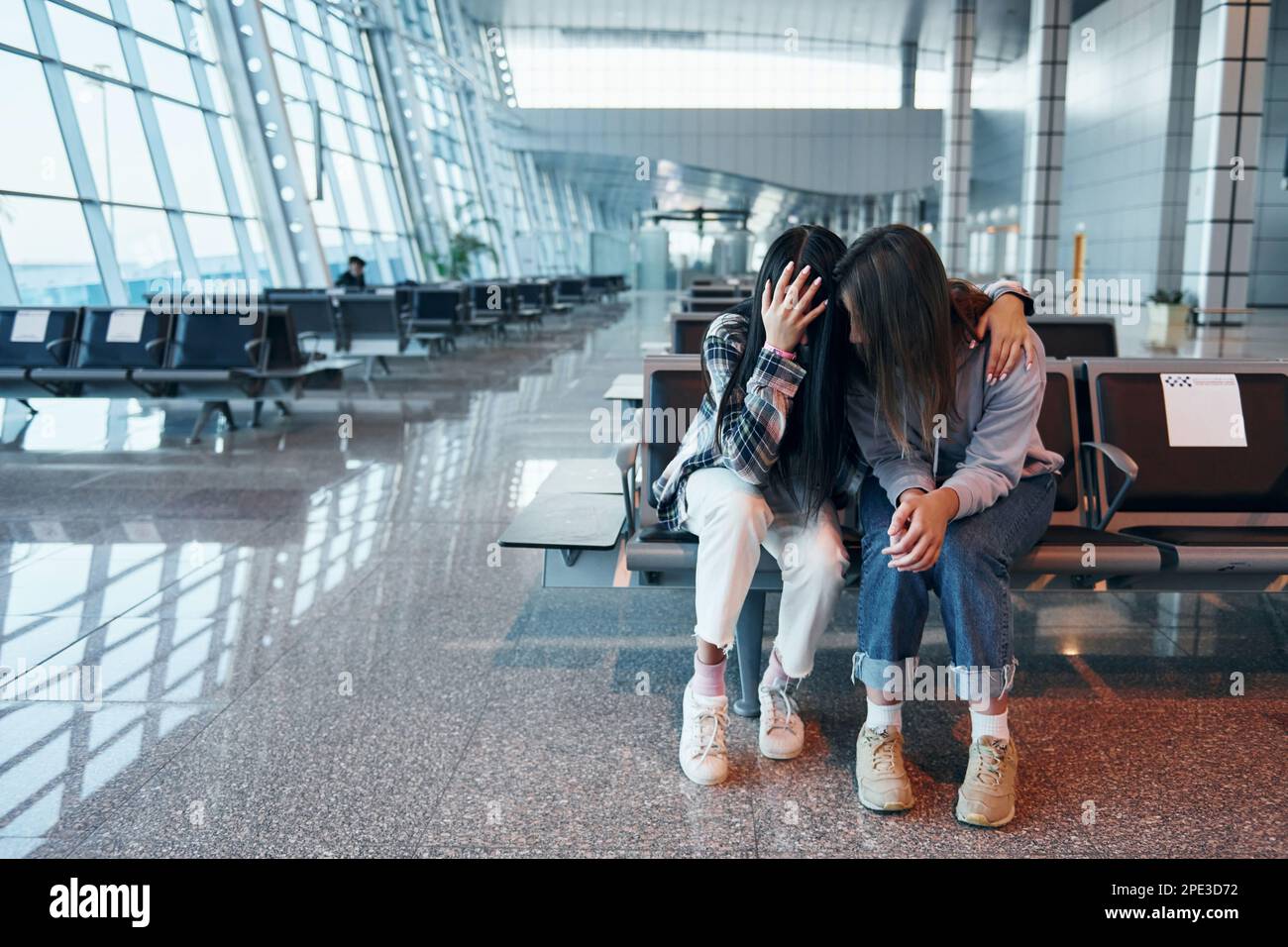Sad young girl crying with her friend when sitting in the modern ...
