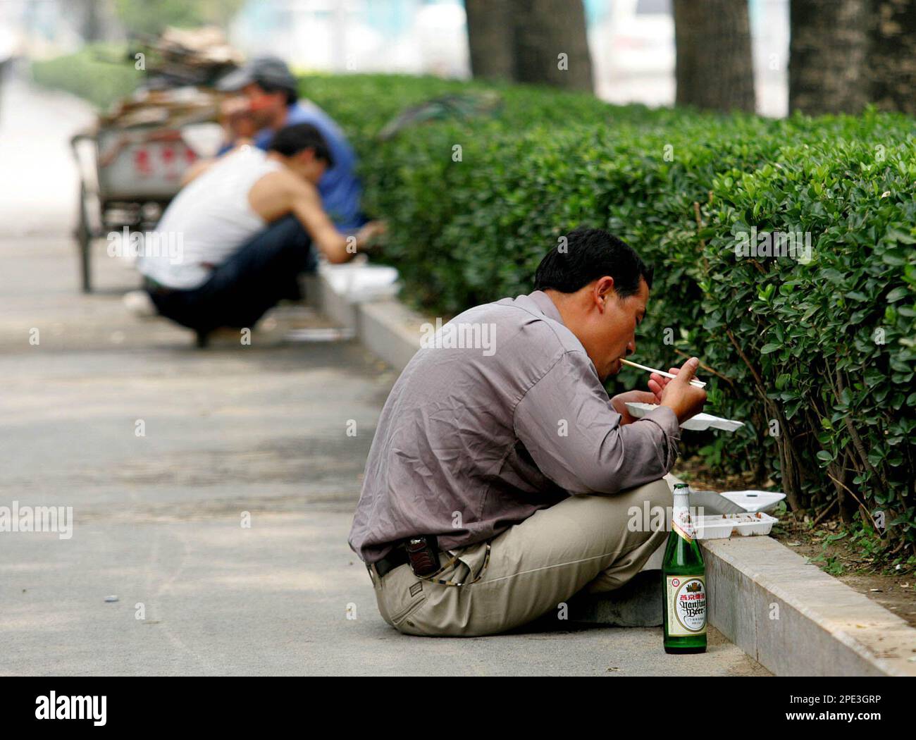 Chinese workers eat their lunch in the gutter of a cycle lane in ...