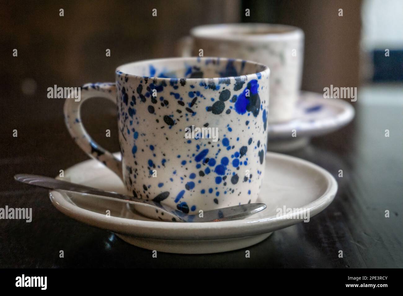 White coffee cup with blue spots on a saucer with a spoon on a wooden ...