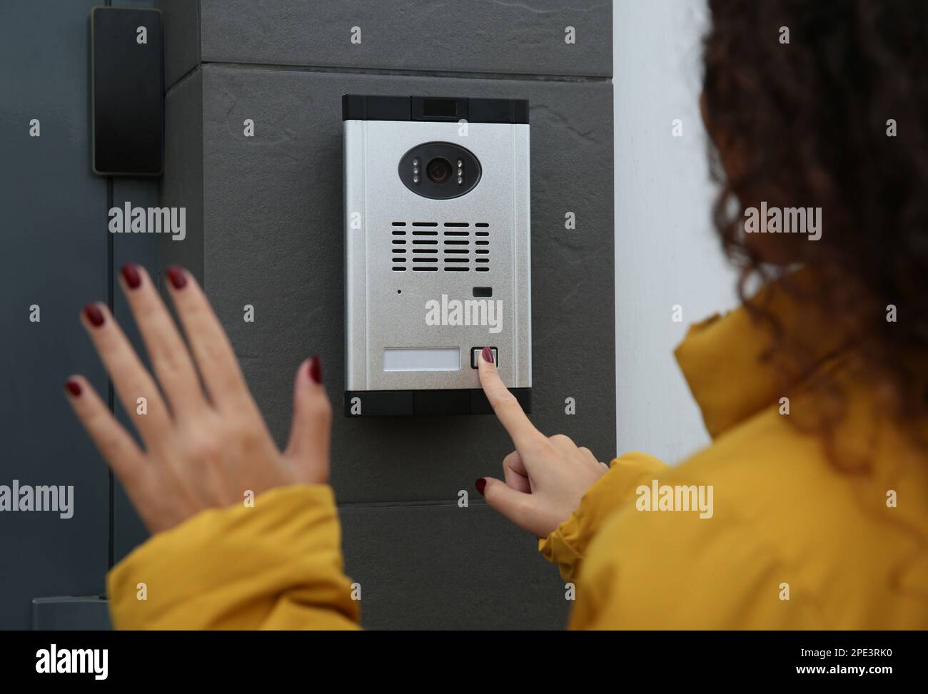 African-American woman ringing intercom while waving to camera near ...