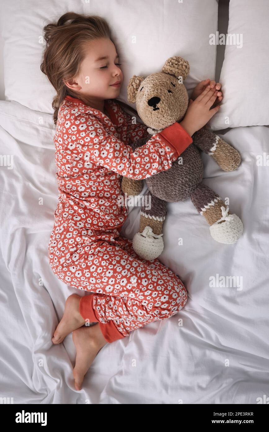 Cute little girl with toy bear sleeping on bed, top view Stock Photo ...