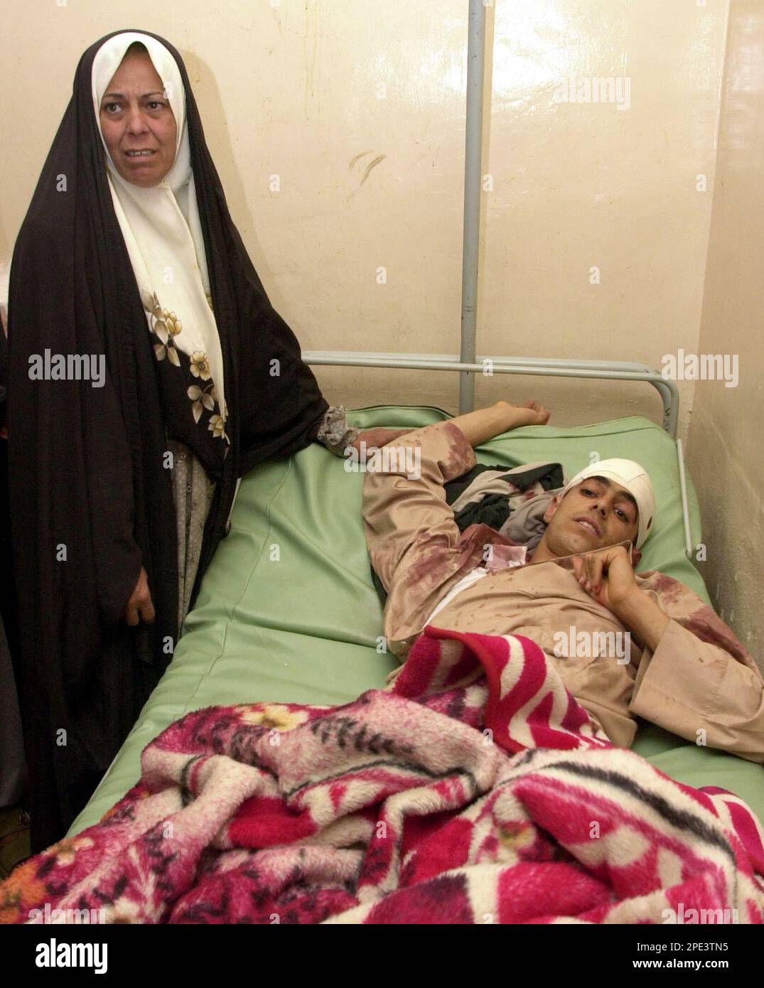 22 year old Ehab Adel lies in hospital comforted by his mother in the Iraqi town of Qaim on the ...