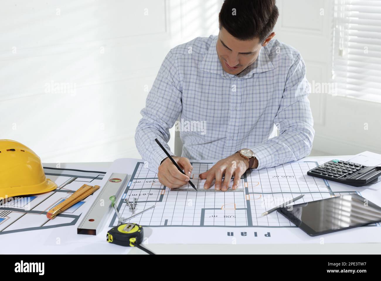Architect working with construction drawings in office Stock Photo - Alamy