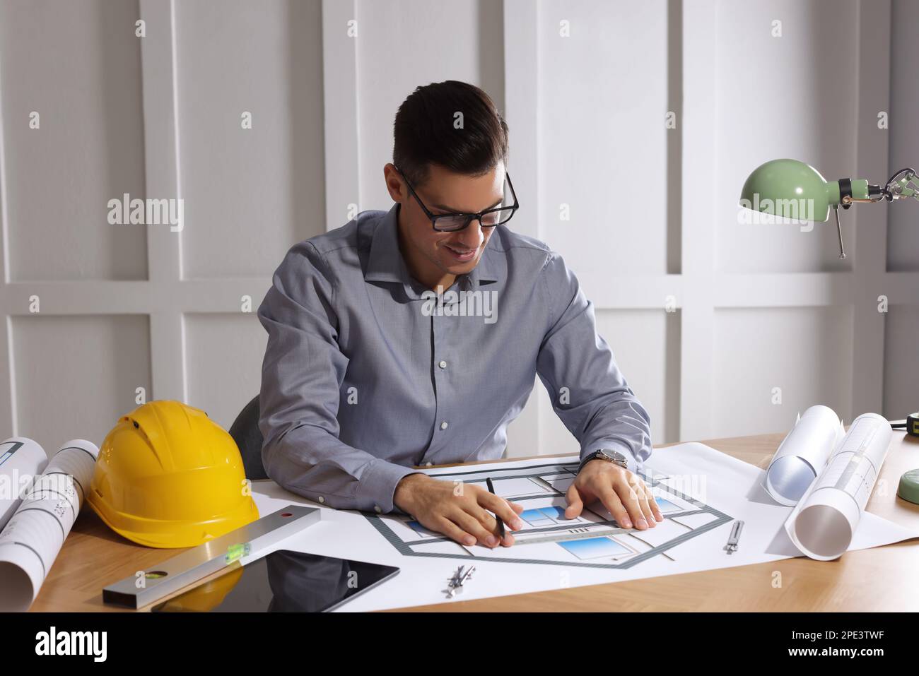 Architect working with construction drawings in office Stock Photo - Alamy
