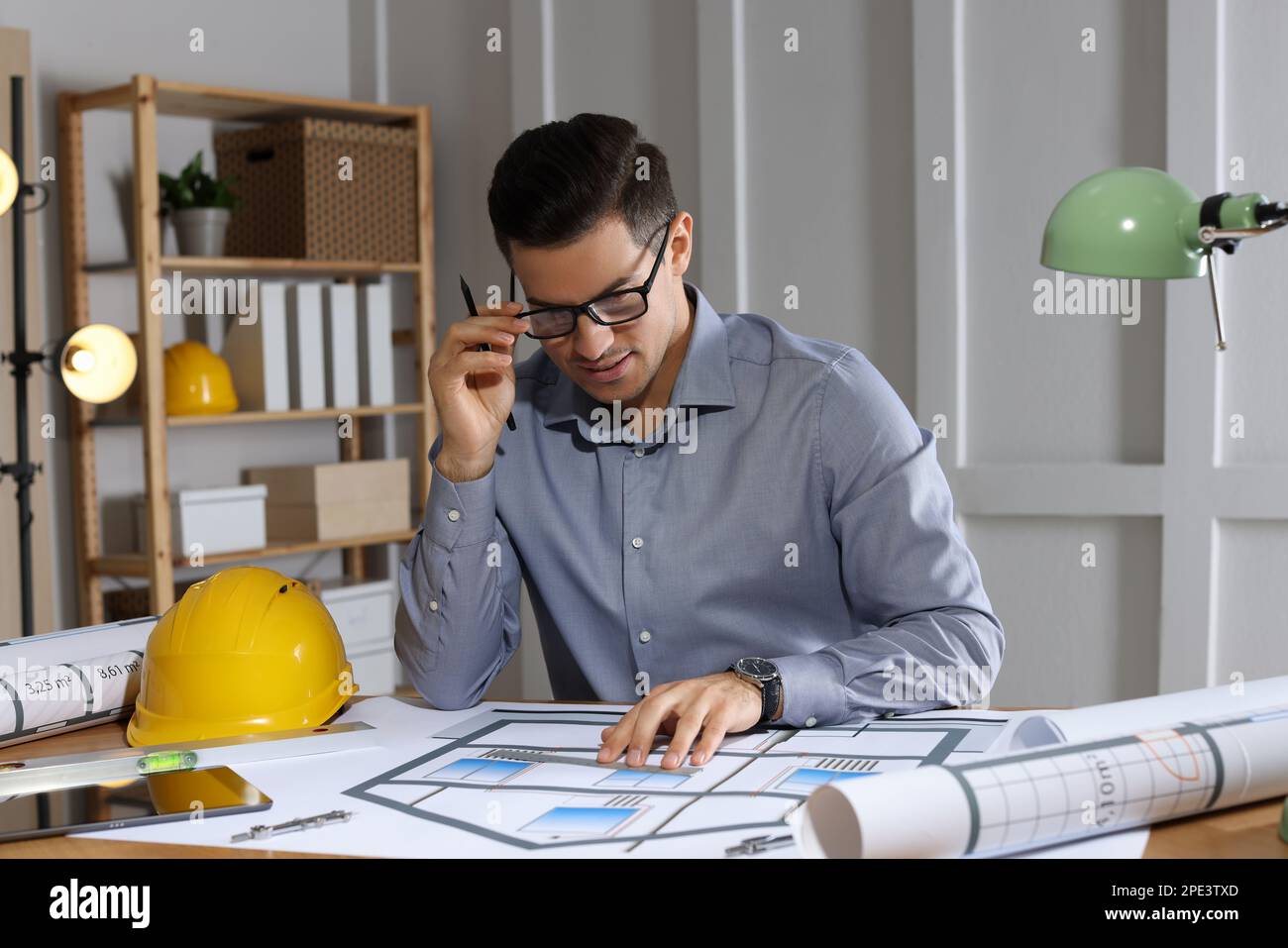 Architect working with construction drawings in office Stock Photo - Alamy