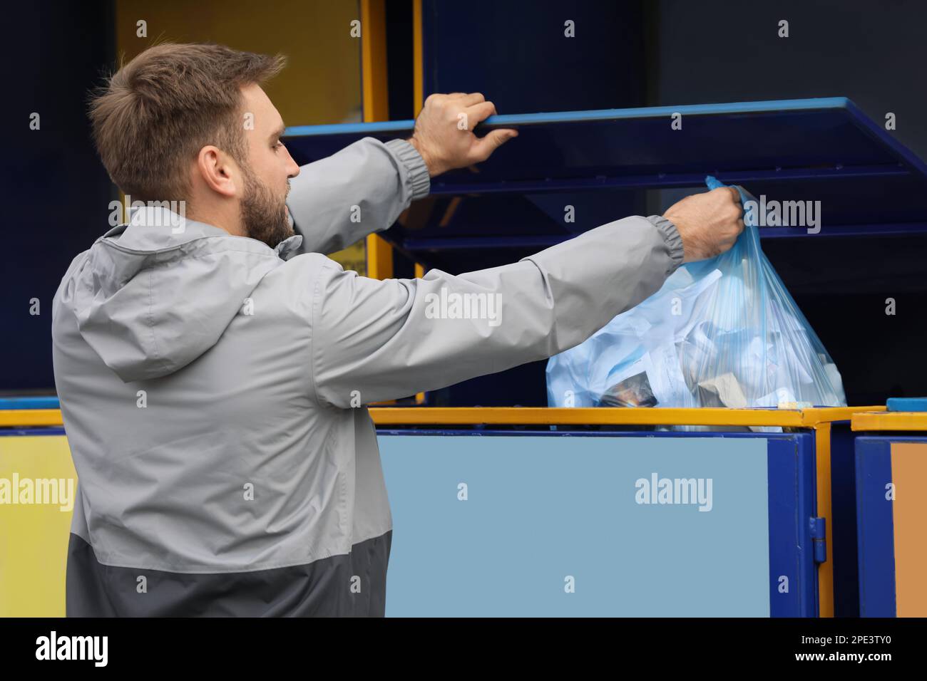 Man throwing garbage into bin at recycling point outdoors Stock Photo ...