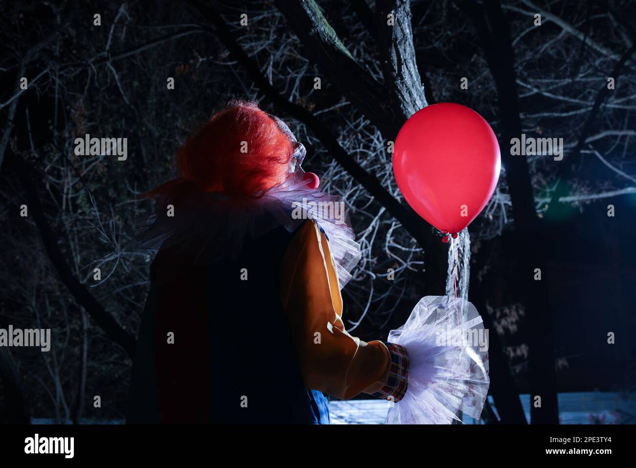 Terrifying clown with red air balloon outdoors at night. Halloween ...