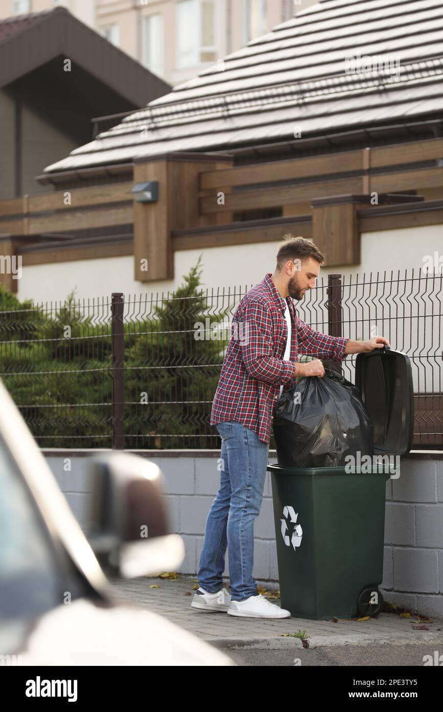 Man putting garbage bag into recycling bin outdoors Stock Photo - Alamy