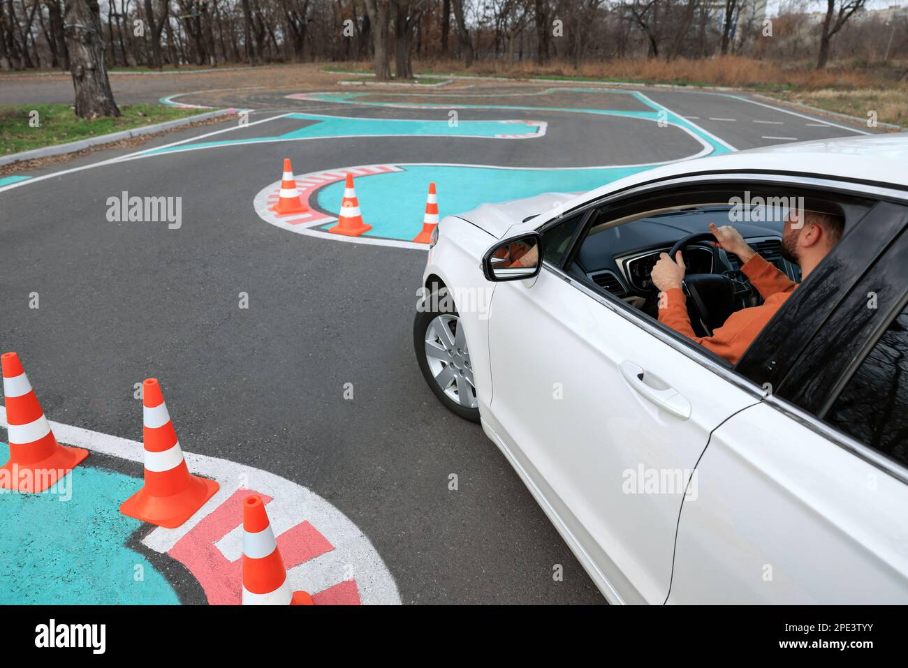 Young man in car on test track with traffic cones, above view. Driving ...