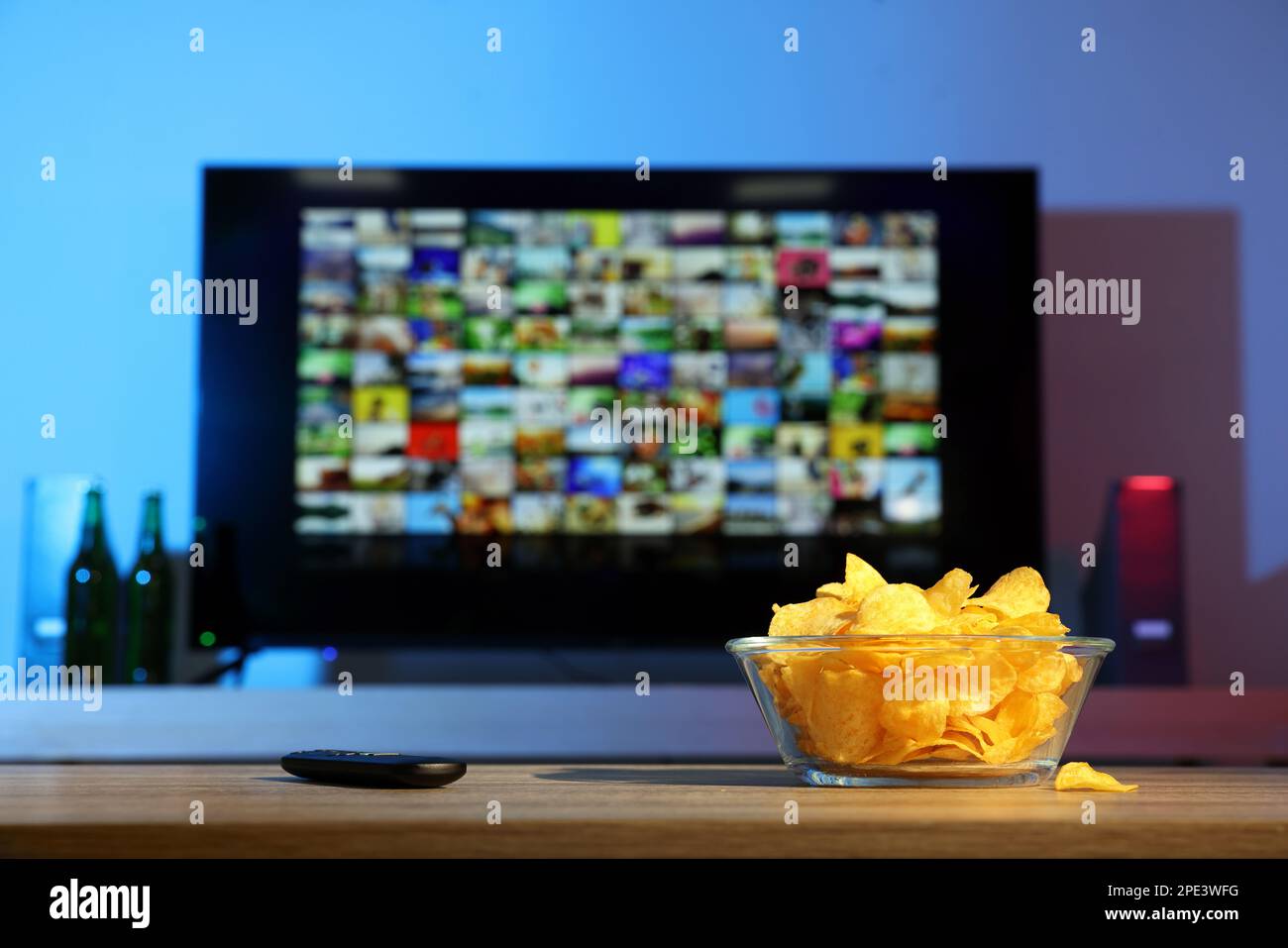 Bowl of chips and TV remote control on table indoors. Space for text ...