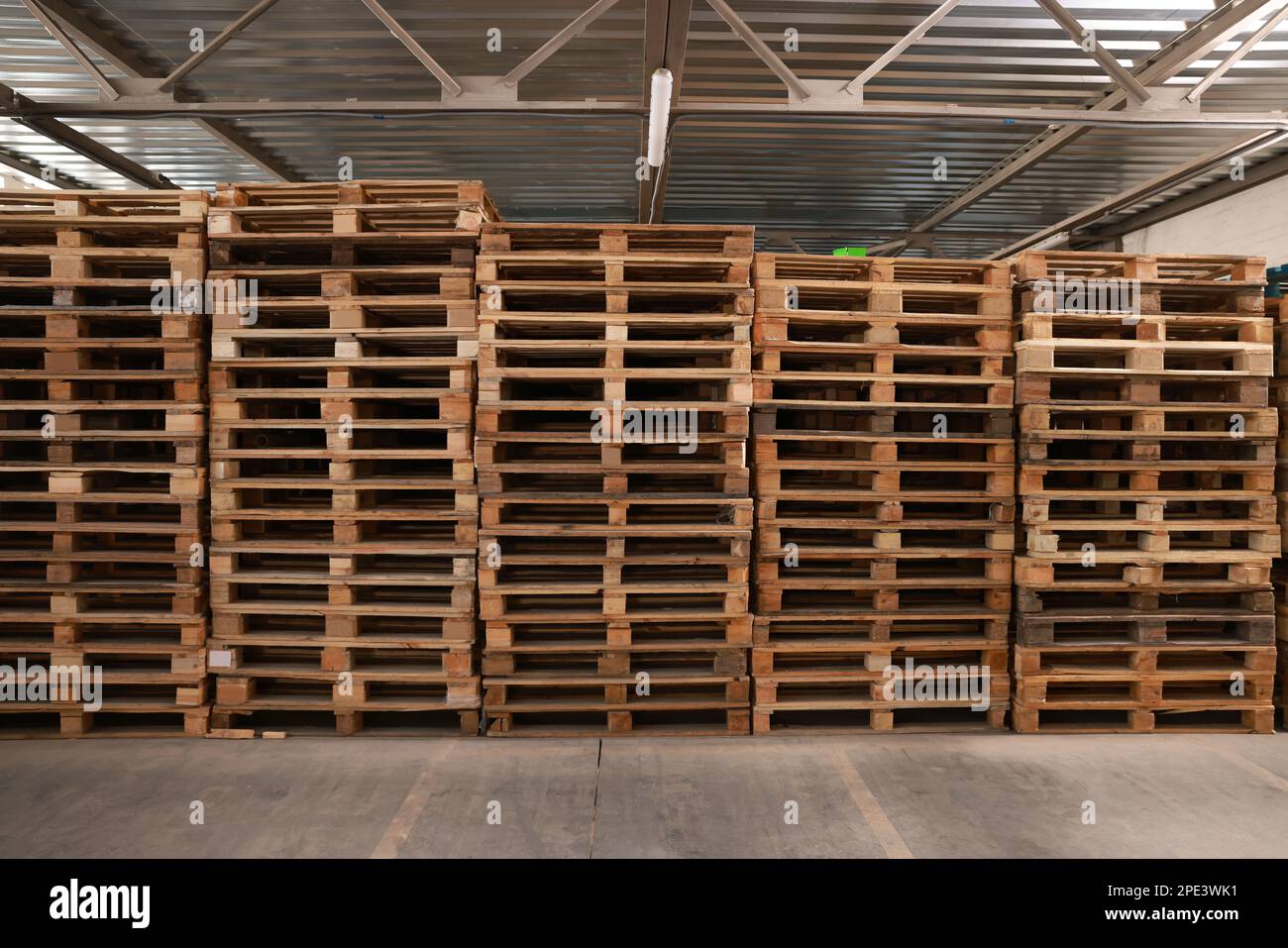 Many empty wooden pallets stacked in warehouse Stock Photo - Alamy