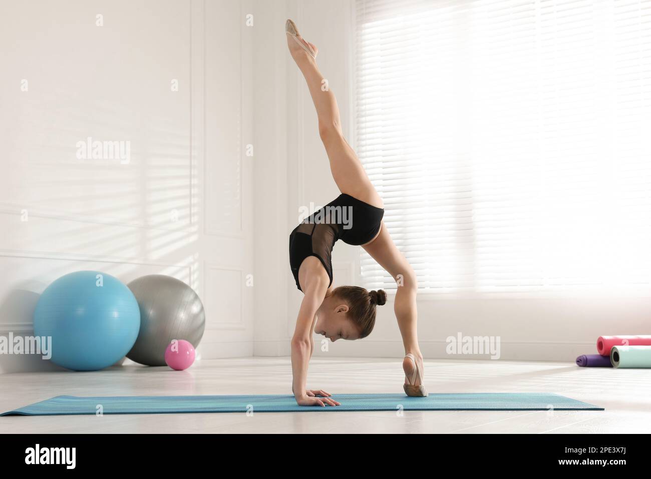 Cute little girl doing gymnastic exercise indoors Stock Photo - Alamy
