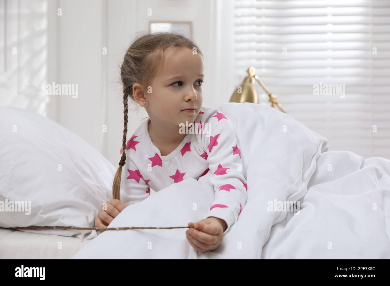 Sad little girl finding tree twig under pillow in bed at home. Saint ...