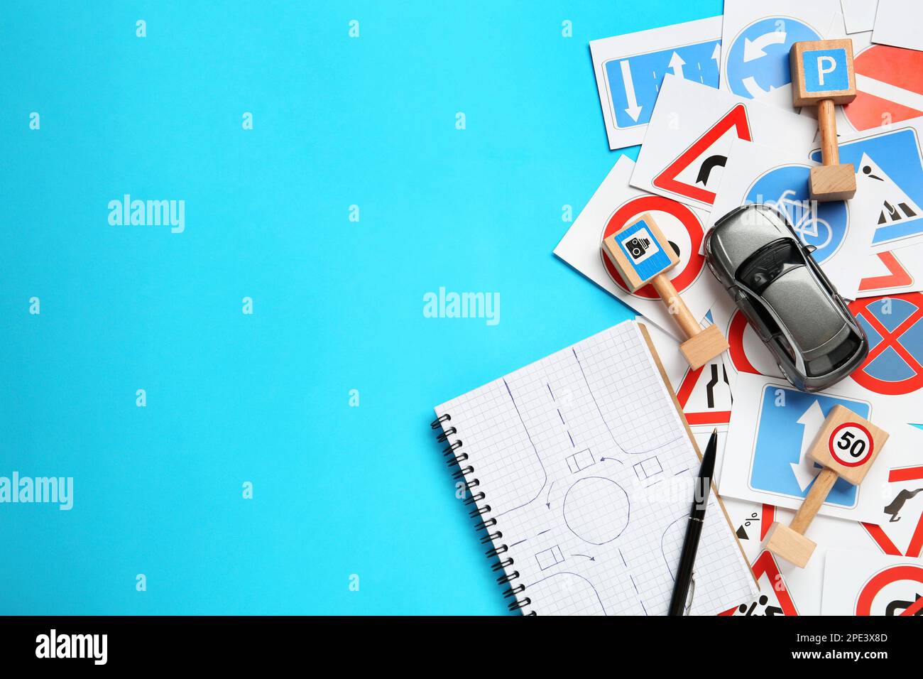Many different road signs, notebook and toy car on light blue ...