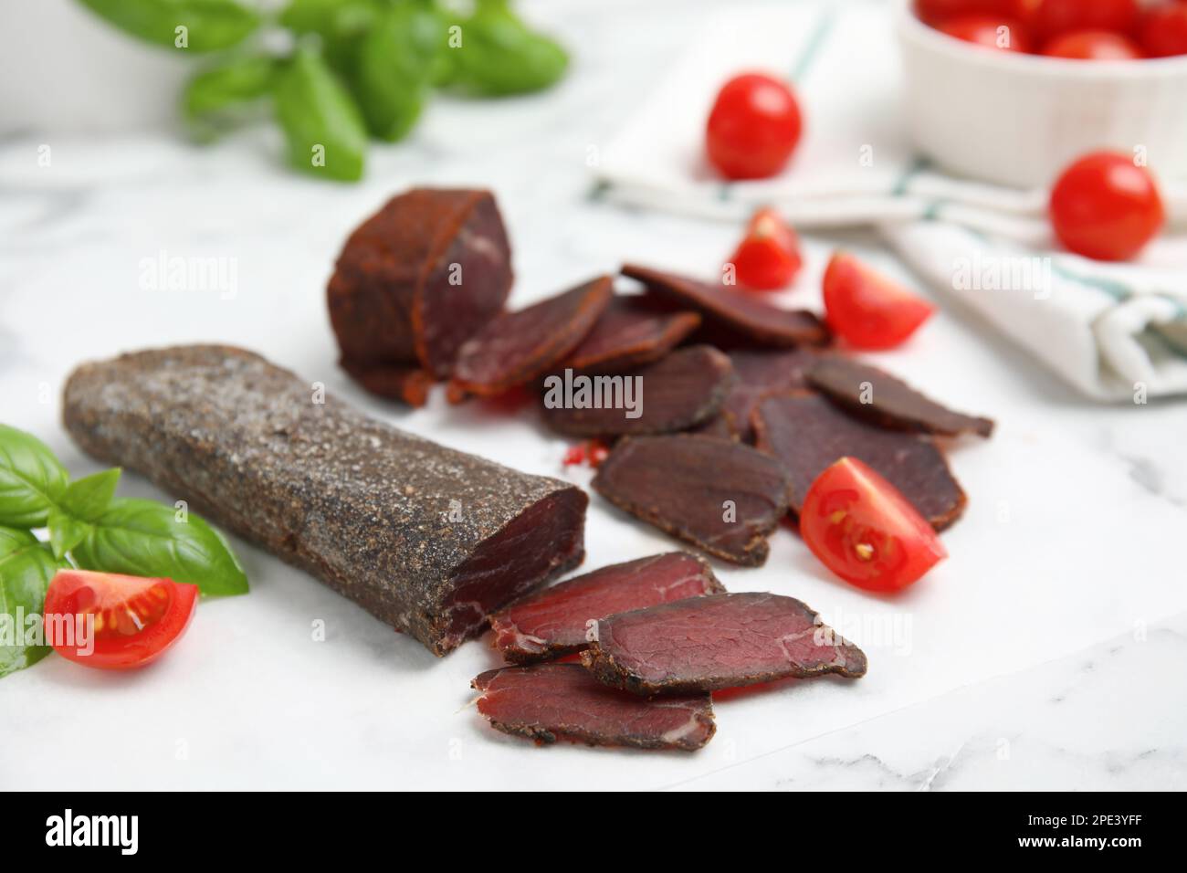 Delicious dry-cured beef basturma with basil and tomatoes on white ...