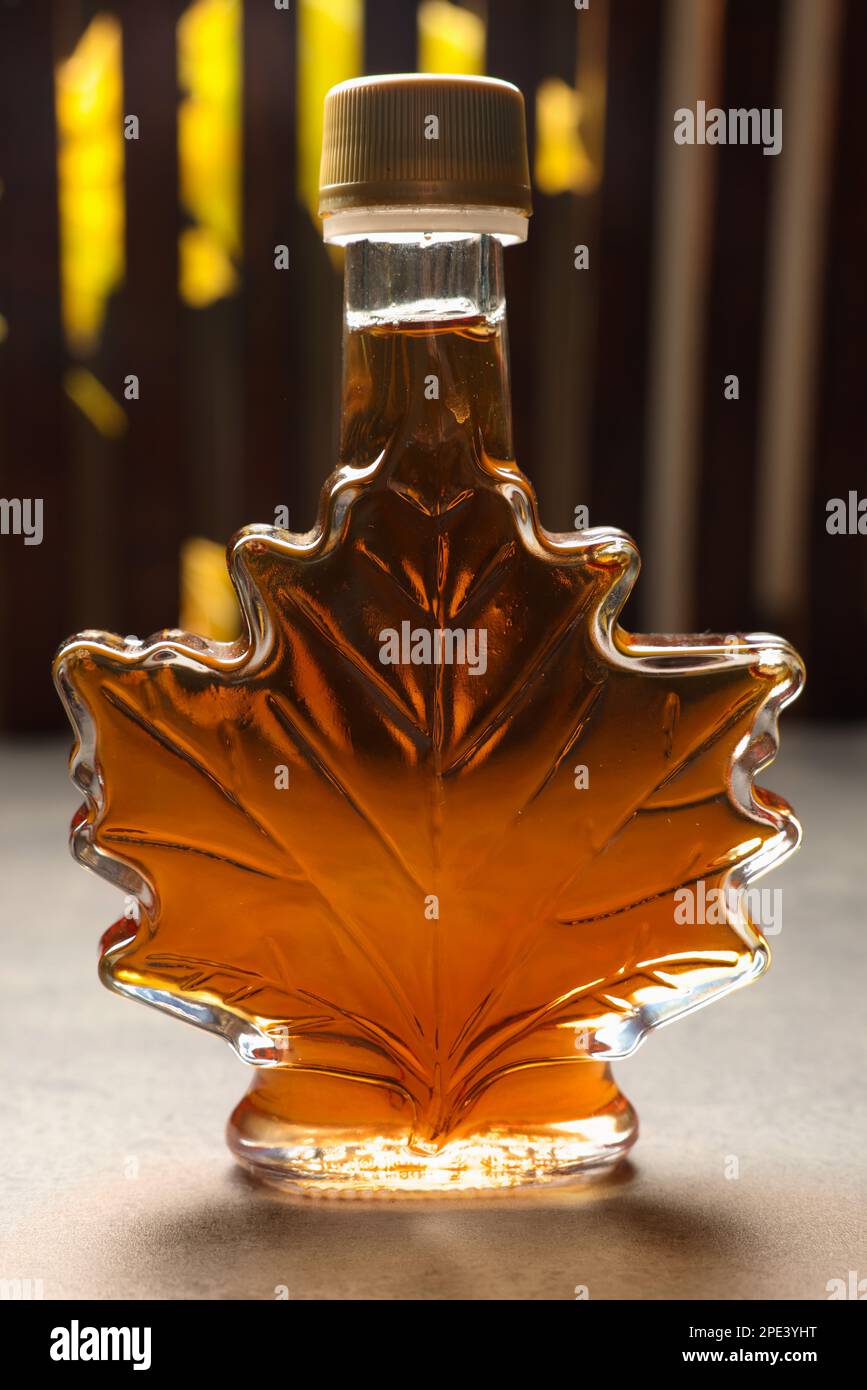 Leaf shaped bottle of tasty maple syrup on light grey table Stock Photo - Alamy