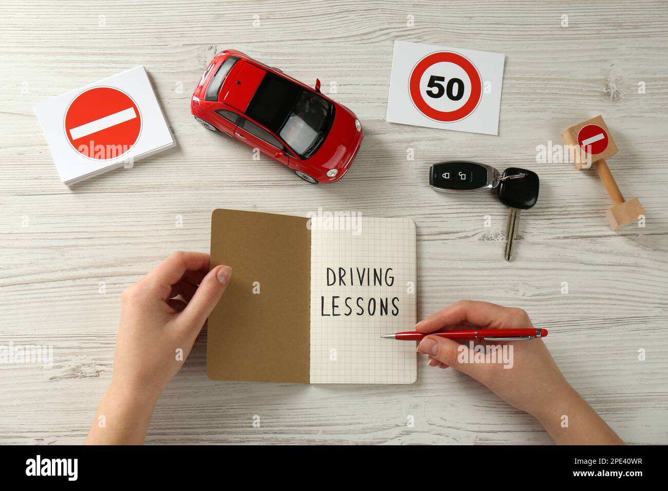Woman with workbook for driving lessons, car key and road signs at ...