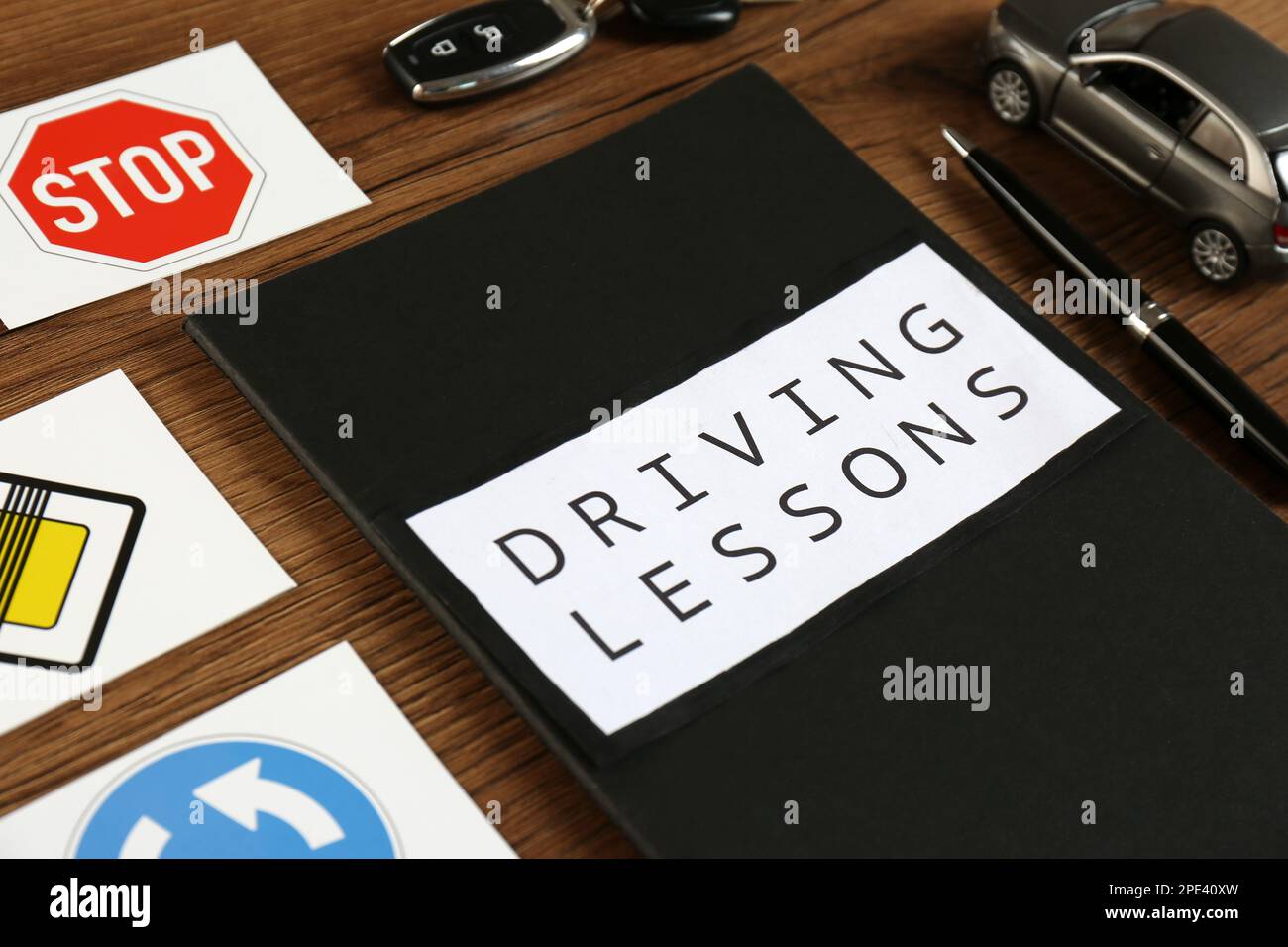 Workbook for driving lessons, pen and road signs on wooden table ...