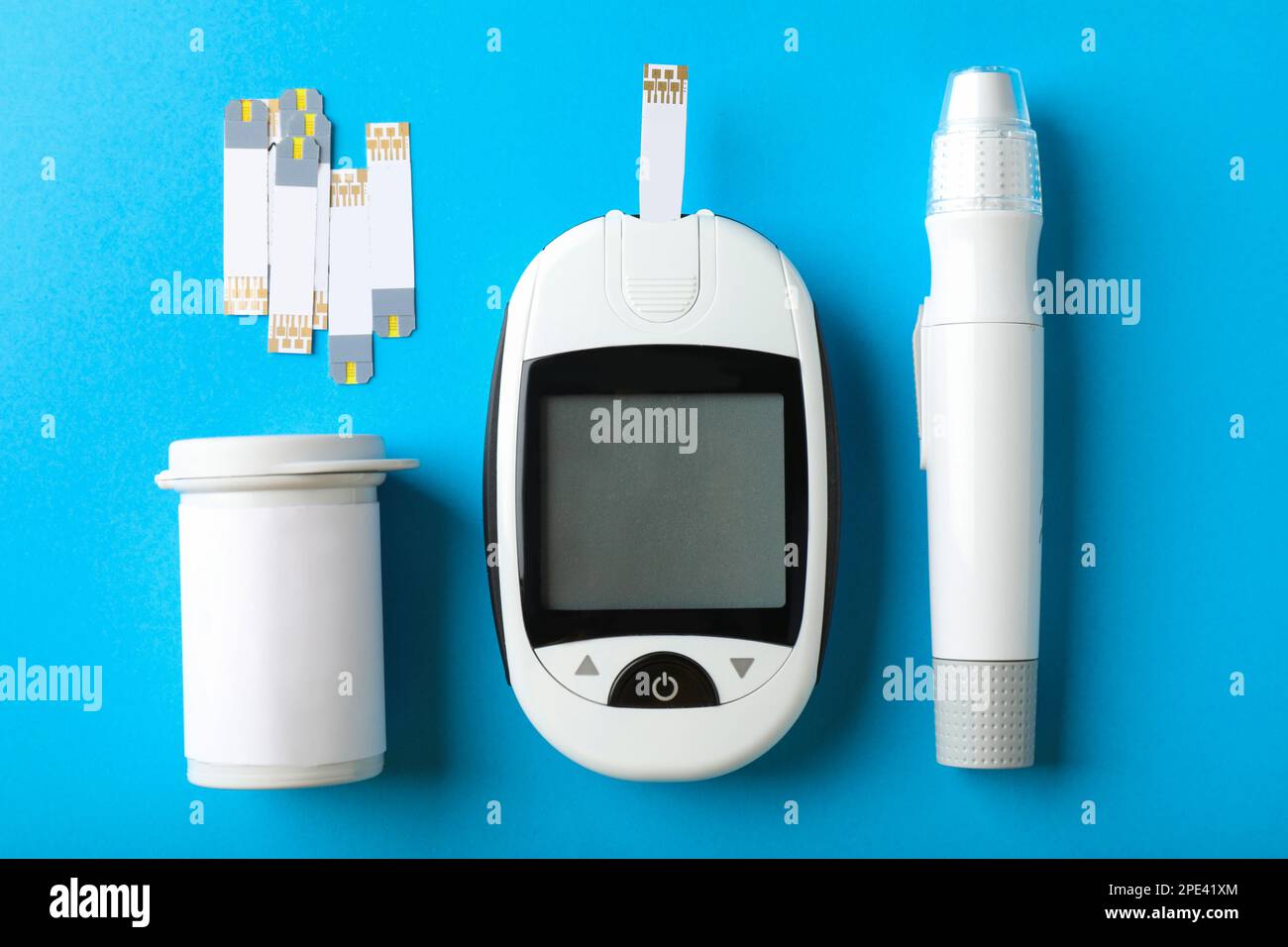 Digital glucometer, lancet pen and test strips on light blue background ...