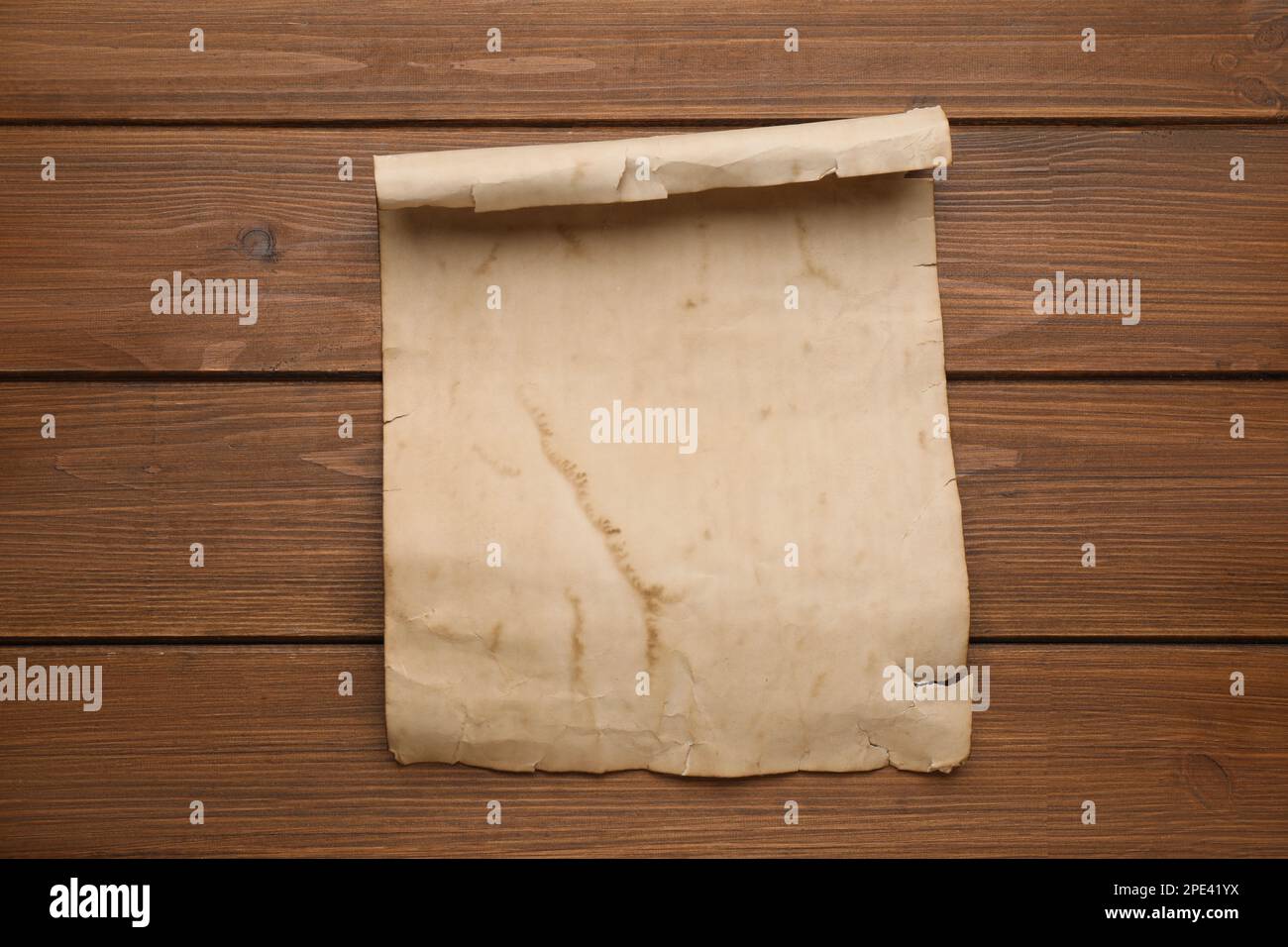 Sheet of old parchment paper on wooden table, top view. Space for ...