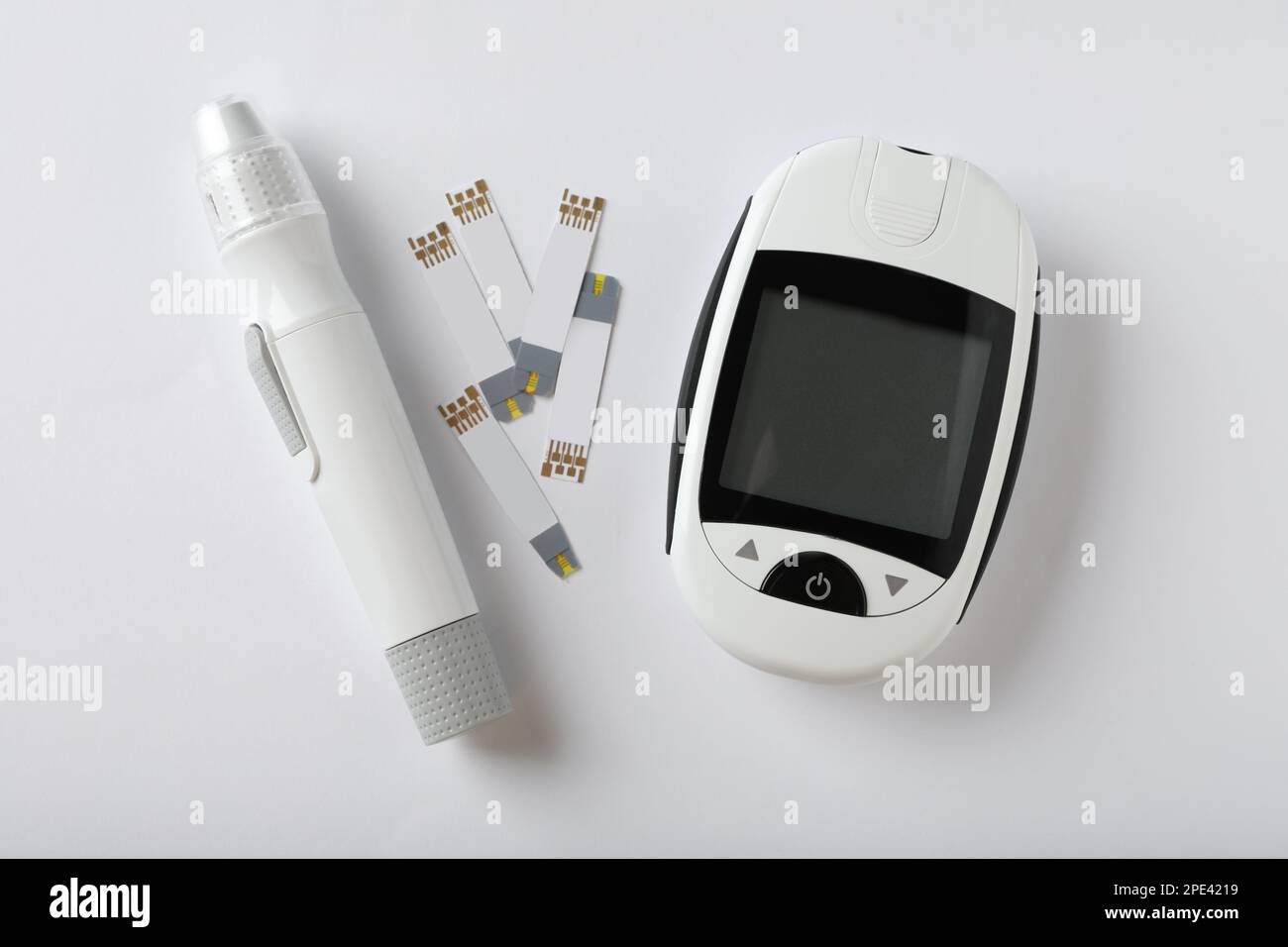 Digital glucometer, lancet pen and test strips on white background ...