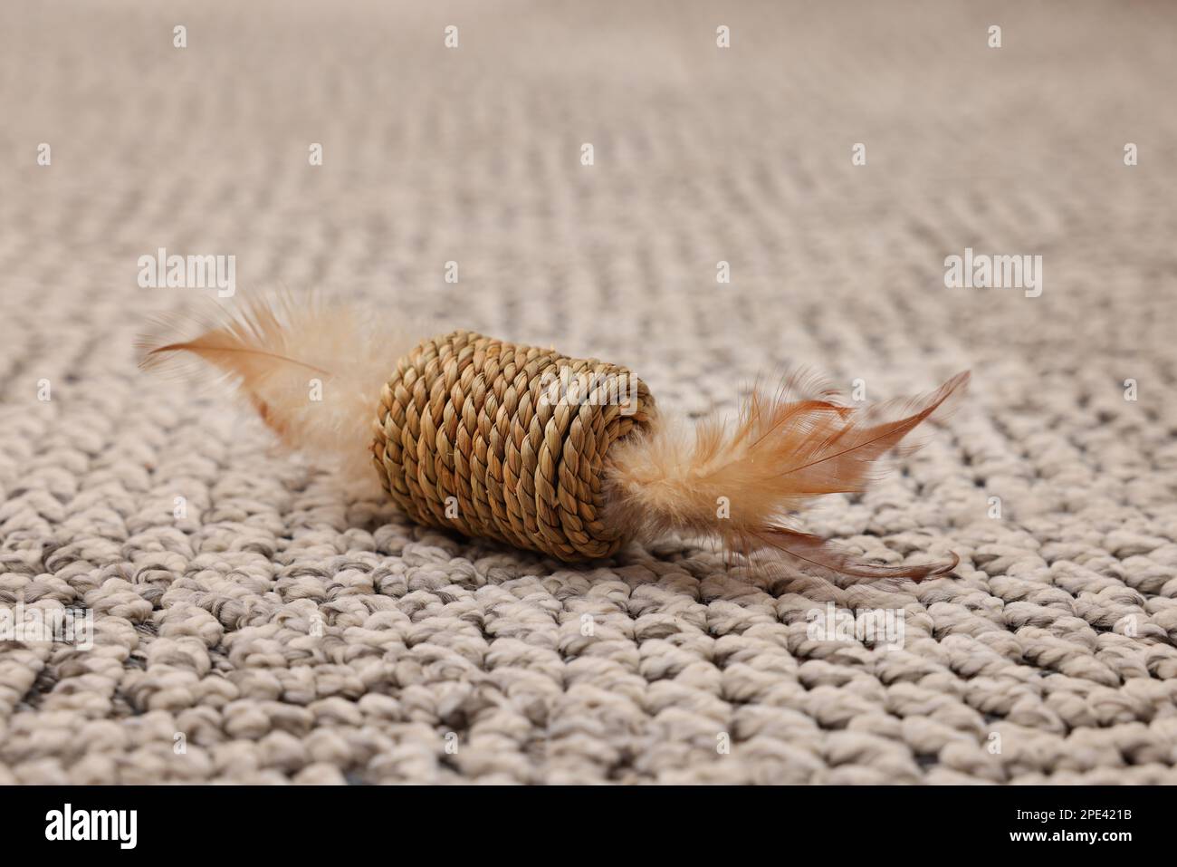 Straw kitten toy with feathers on carpet Stock Photo - Alamy