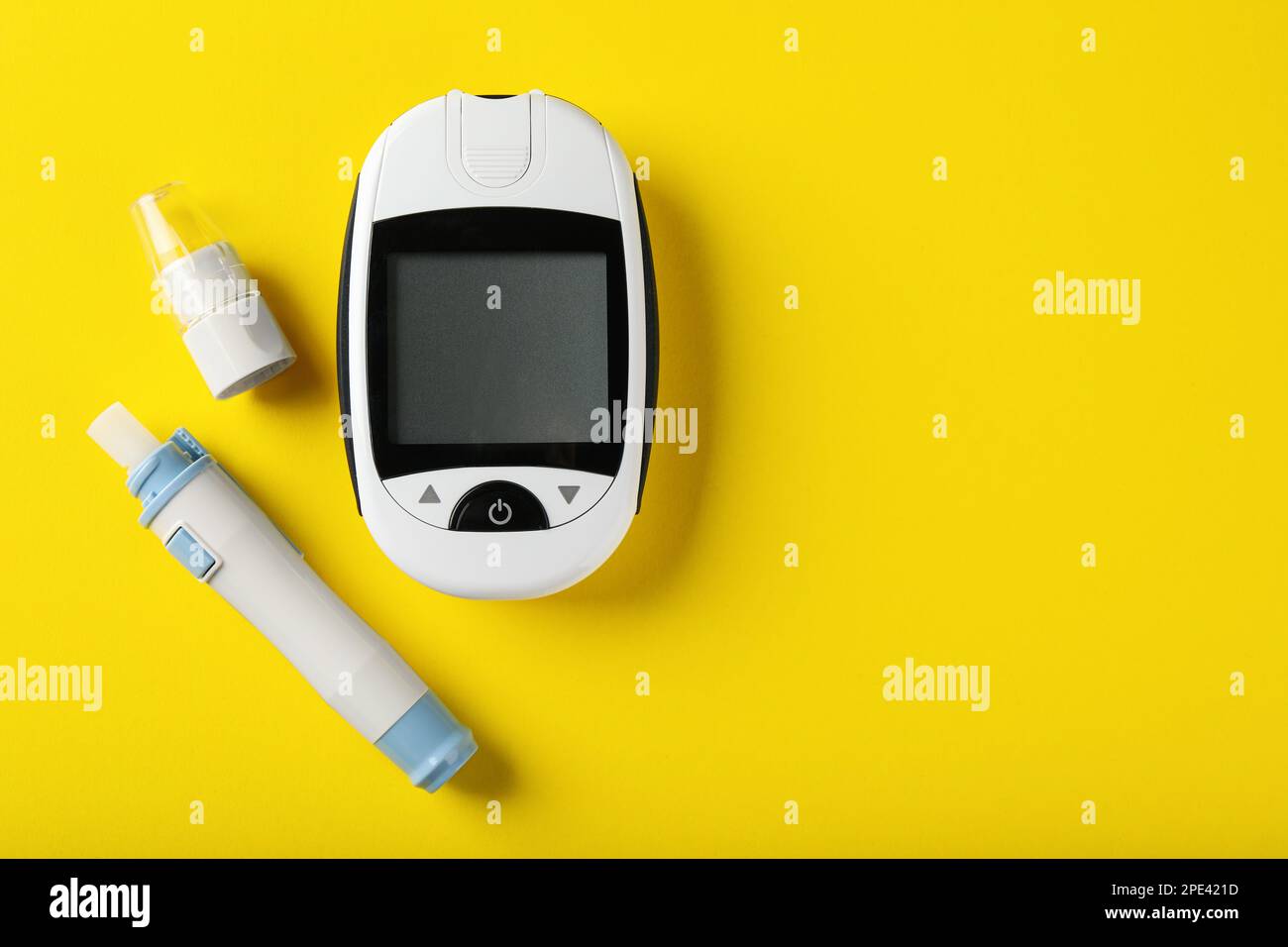 Digital glucometer and lancet pen on yellow background, flat lay with ...