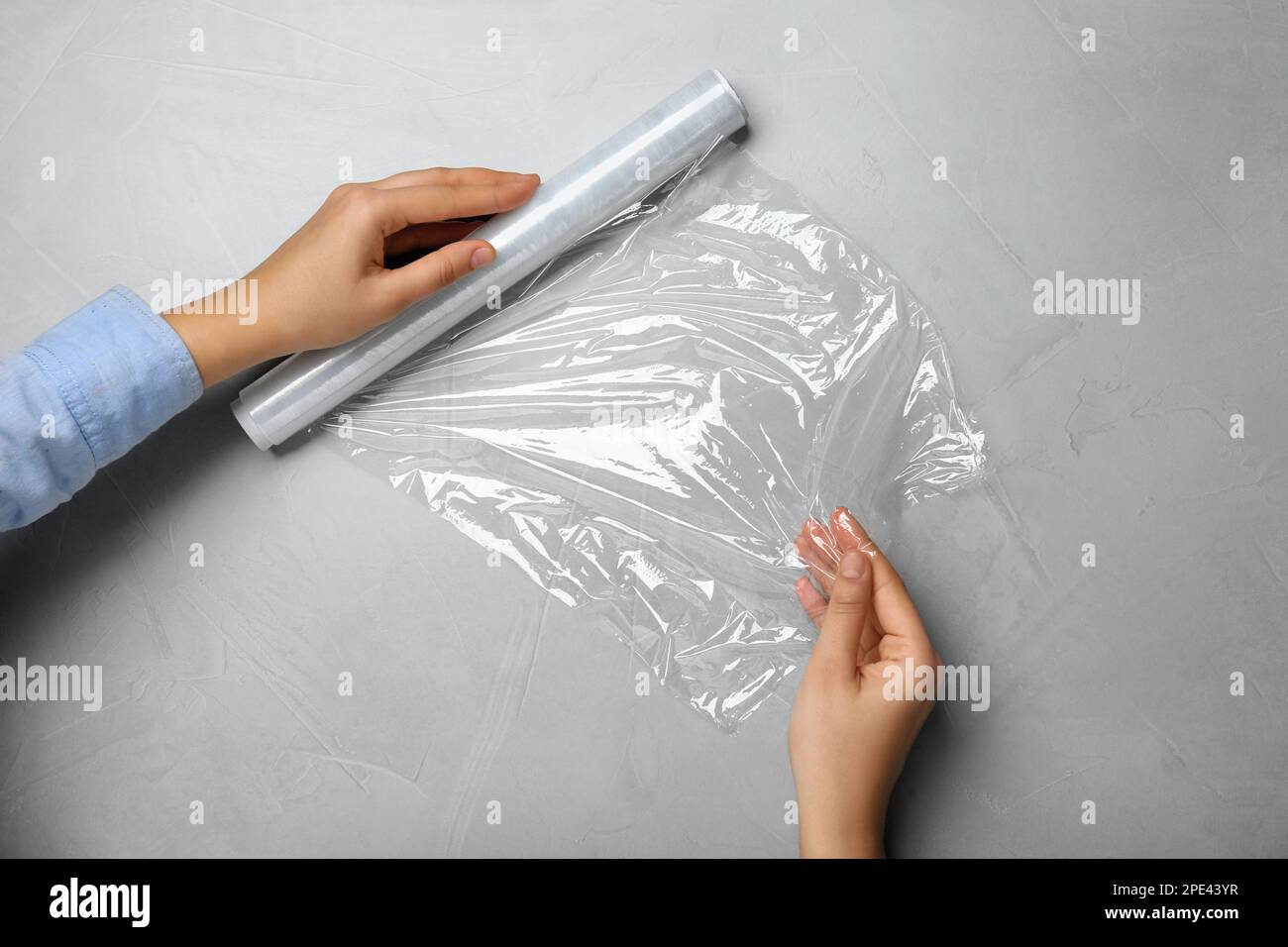 Woman with roll of stretch wrap at light grey table, top view Stock ...