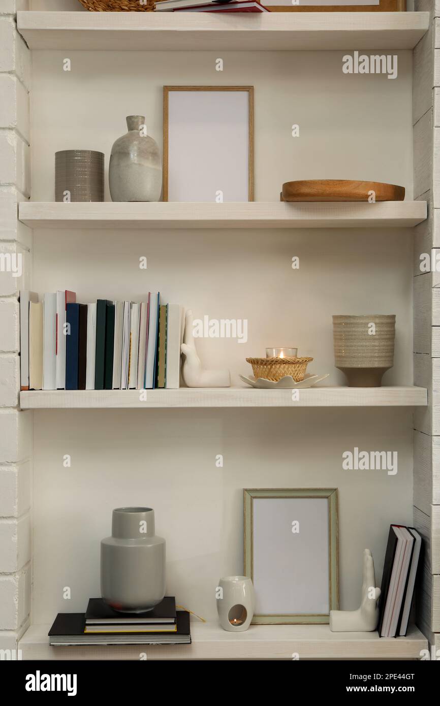 Books, empty frames and different decor on shelves indoors. Interior ...