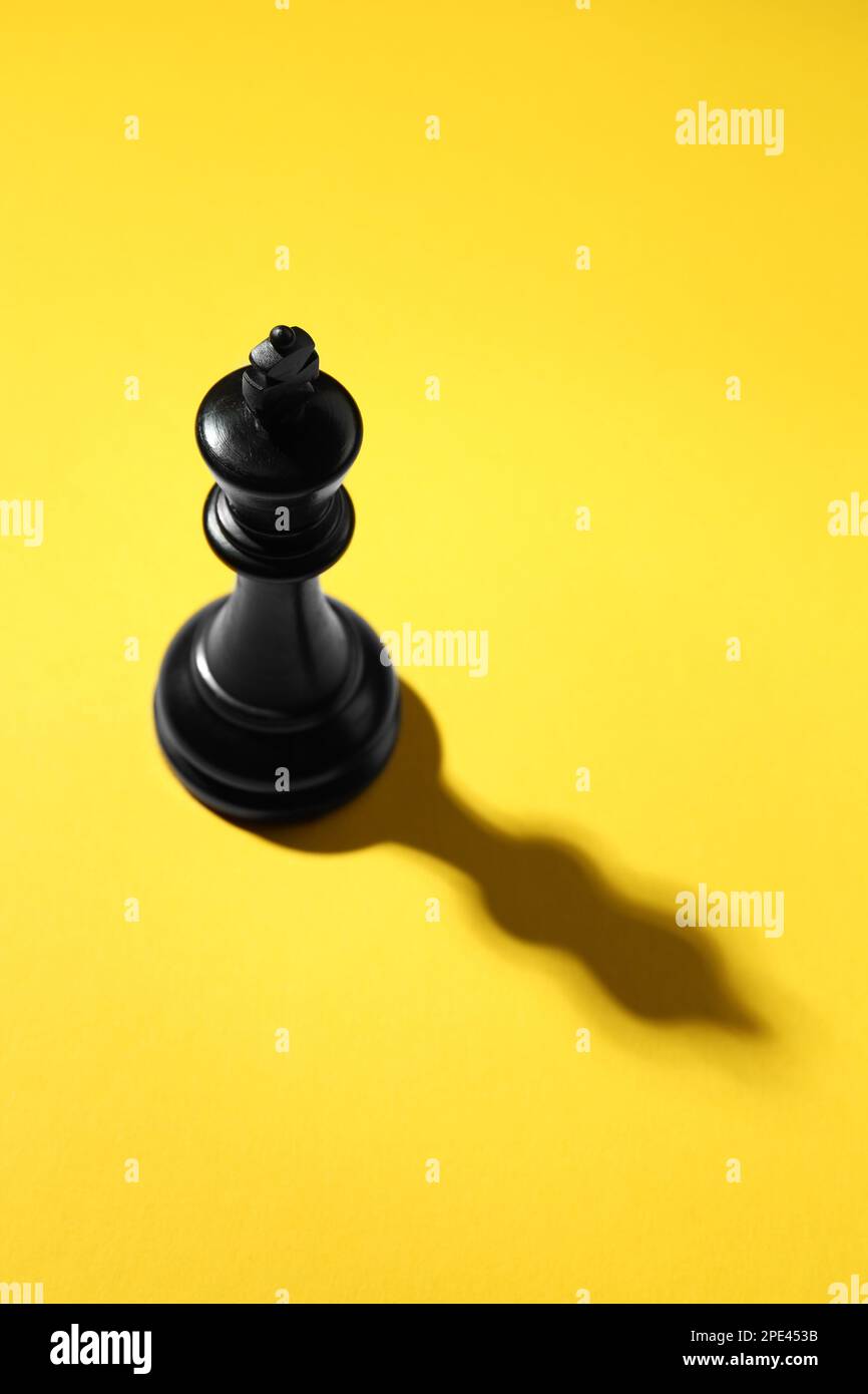 Black wooden chess king on yellow background, above view Stock Photo ...