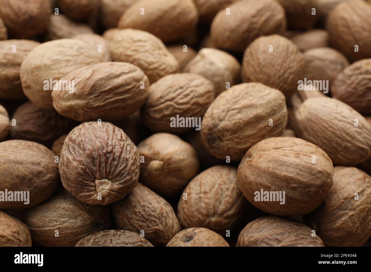 Heap of nutmeg seeds as background, closeup Stock Photo - Alamy