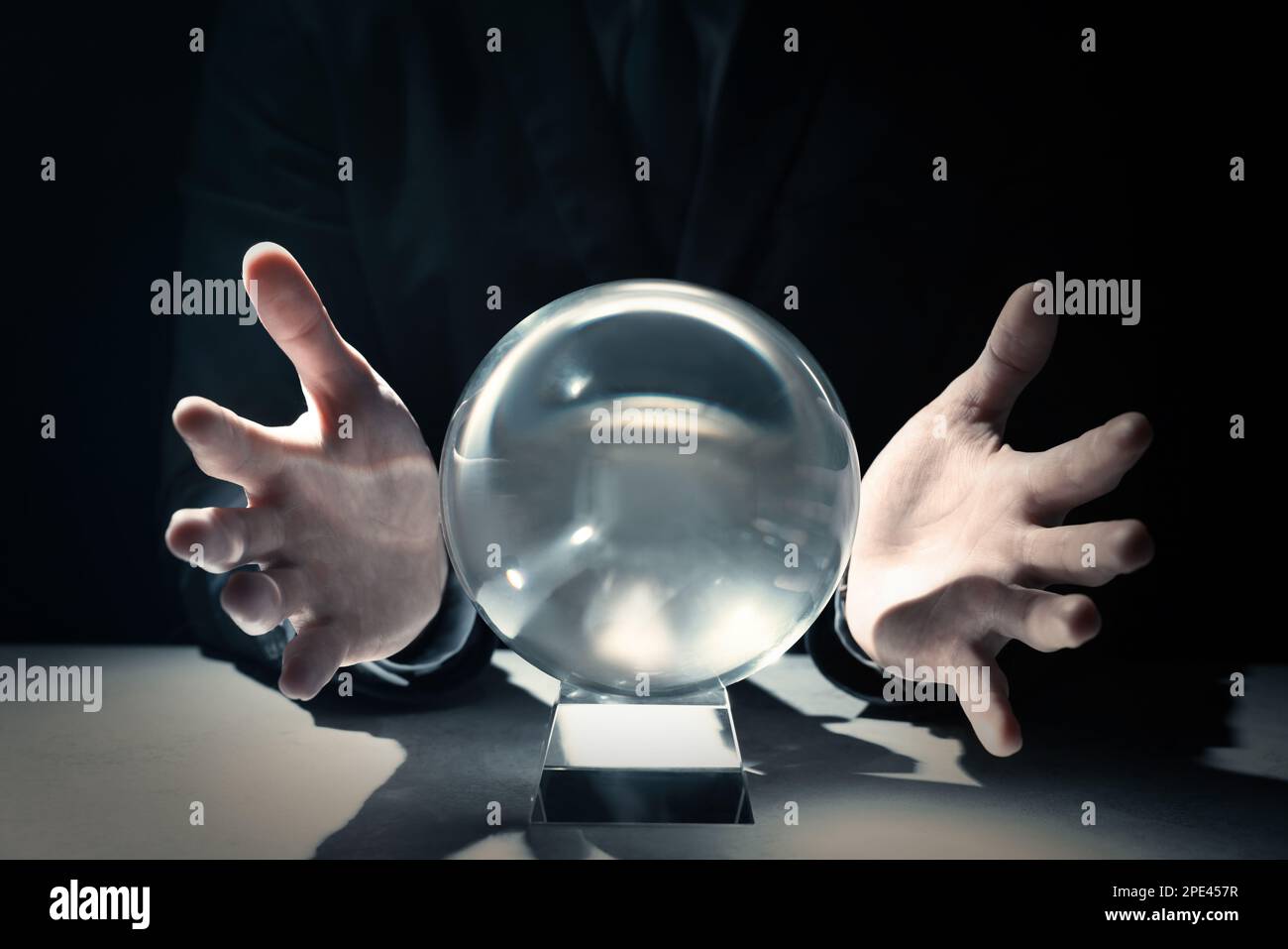 Businessman using crystal ball to predict future at table in darkness ...