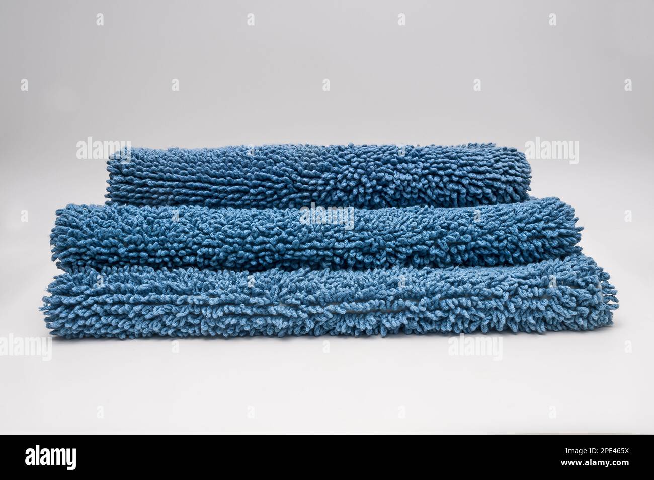 A stack of 3 different sized blue loop throw rugs Stock Photo - Alamy
