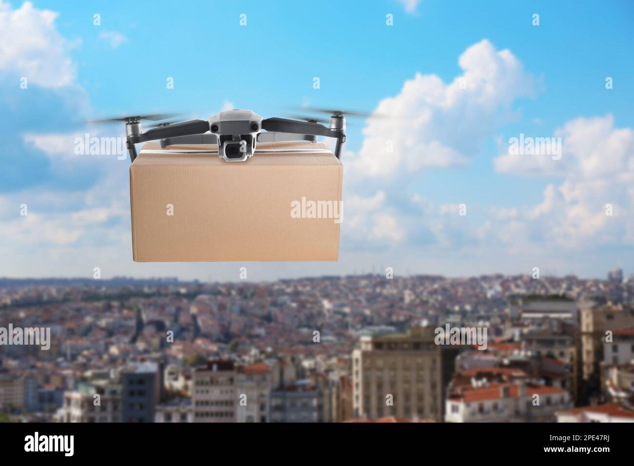 Modern drone with carton box flying above city on sunny day. Delivery ...