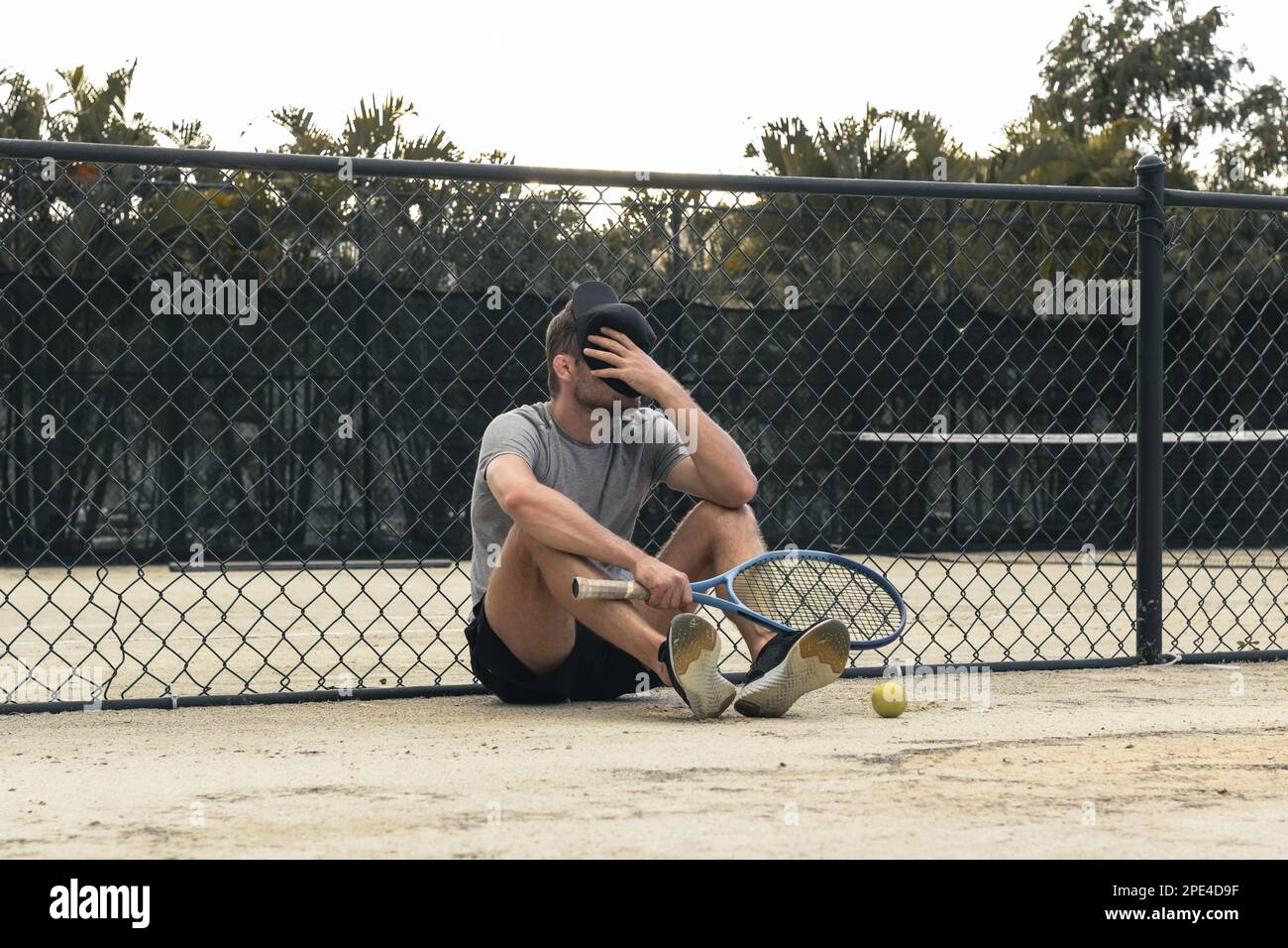 Sad tennis player sitting on court closing his face with cap Stock ...
