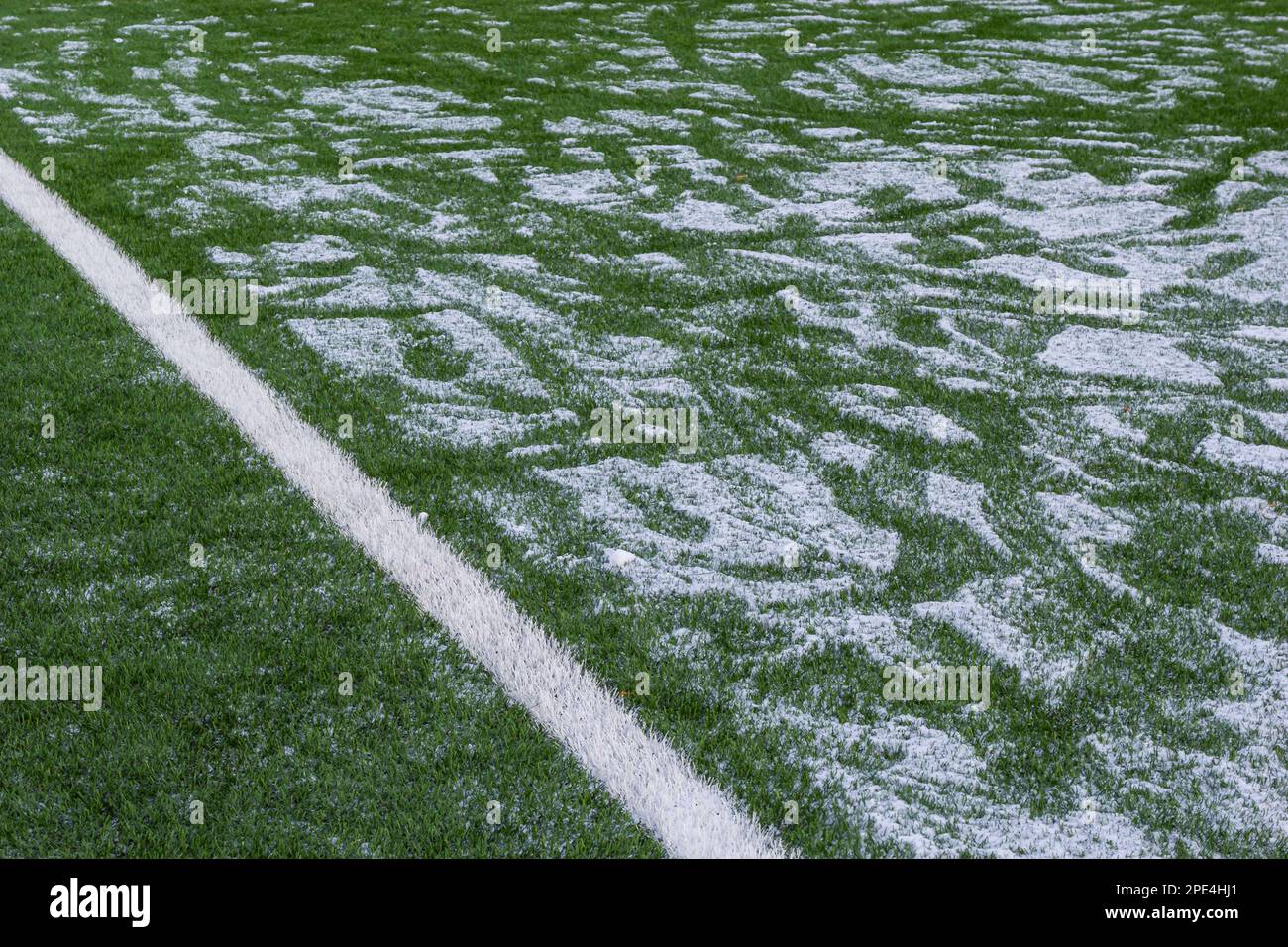 The football field with artificial green grass is covered with a light ...