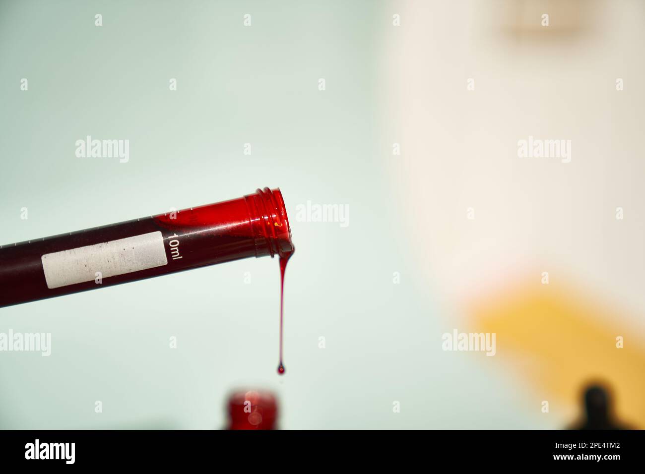 Transparent tubes in a tilt with a drop of blood and a red lid with a ...