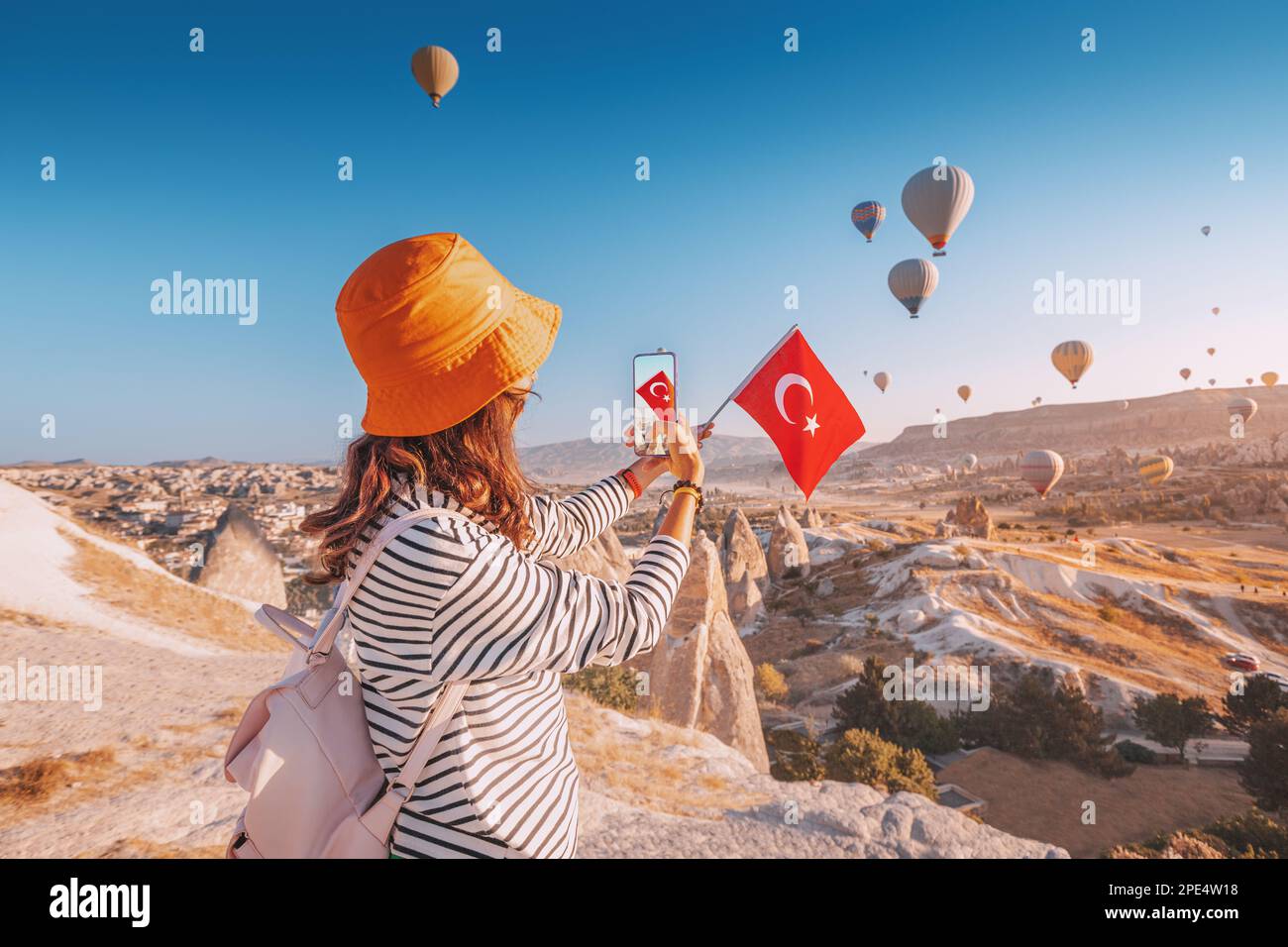 a travel blogger girl takes photos of flying balloons in Cappadocia and ...