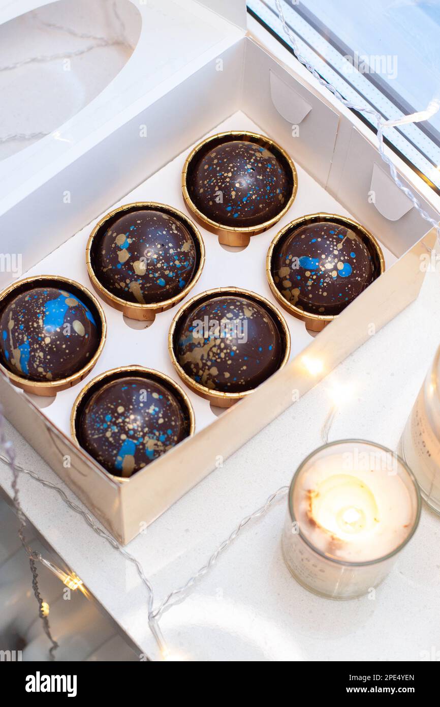 Chocolate spheres in golden gift box with burning candle Stock Photo ...