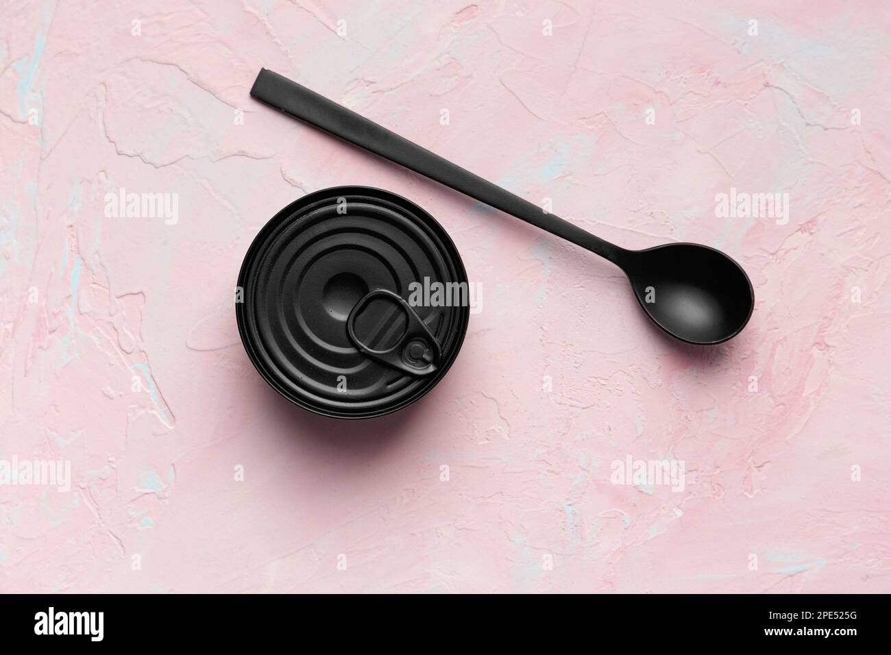 Black matte round closed tin can and black spoon on texture background ...