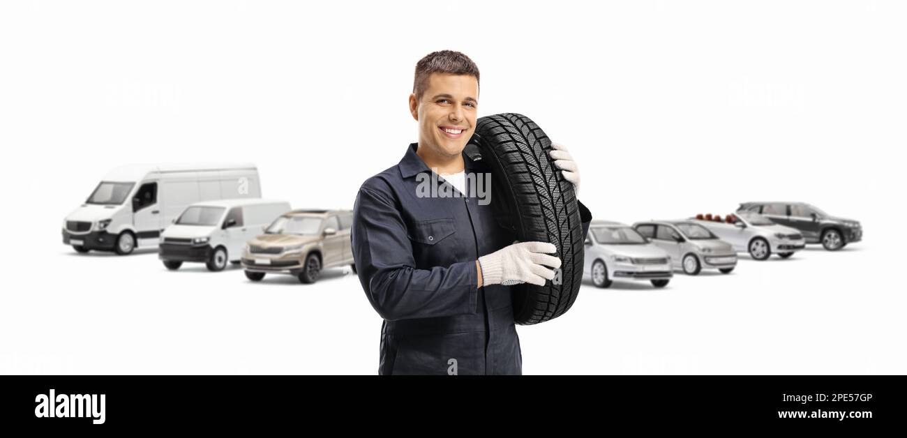 Auto mechanic worker with many vehicles carrying a tire on shoulder and ...