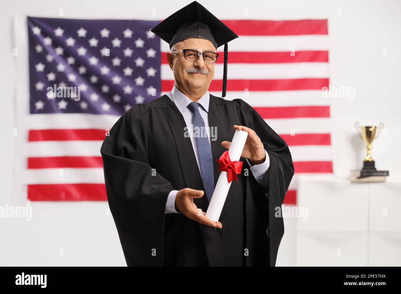 University dean in a graduation gown holding a diploma in front of a ...