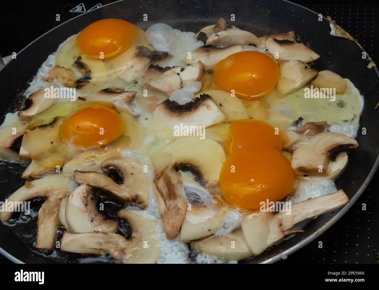 Fried mushrooms and eggs in a pan. The process of cooking breakfast ...