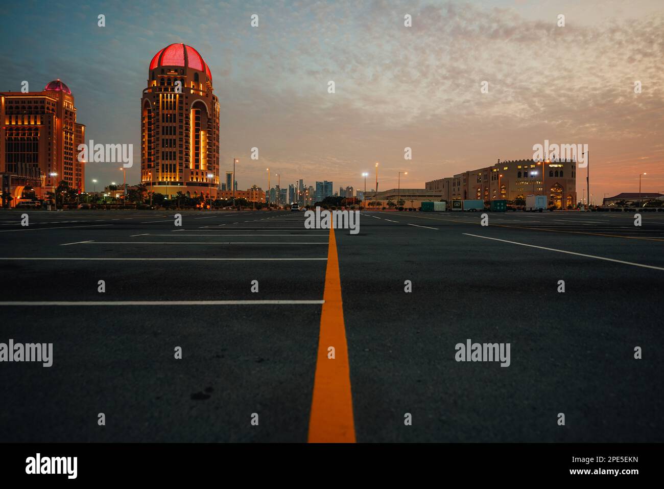 A big empty parking lot at sunset with buildings in the background in ...
