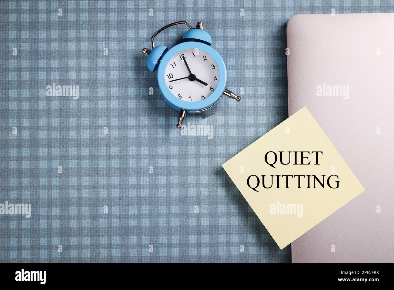 quote 'Quiet quitting' on yellow sticker on computer with clock and ...