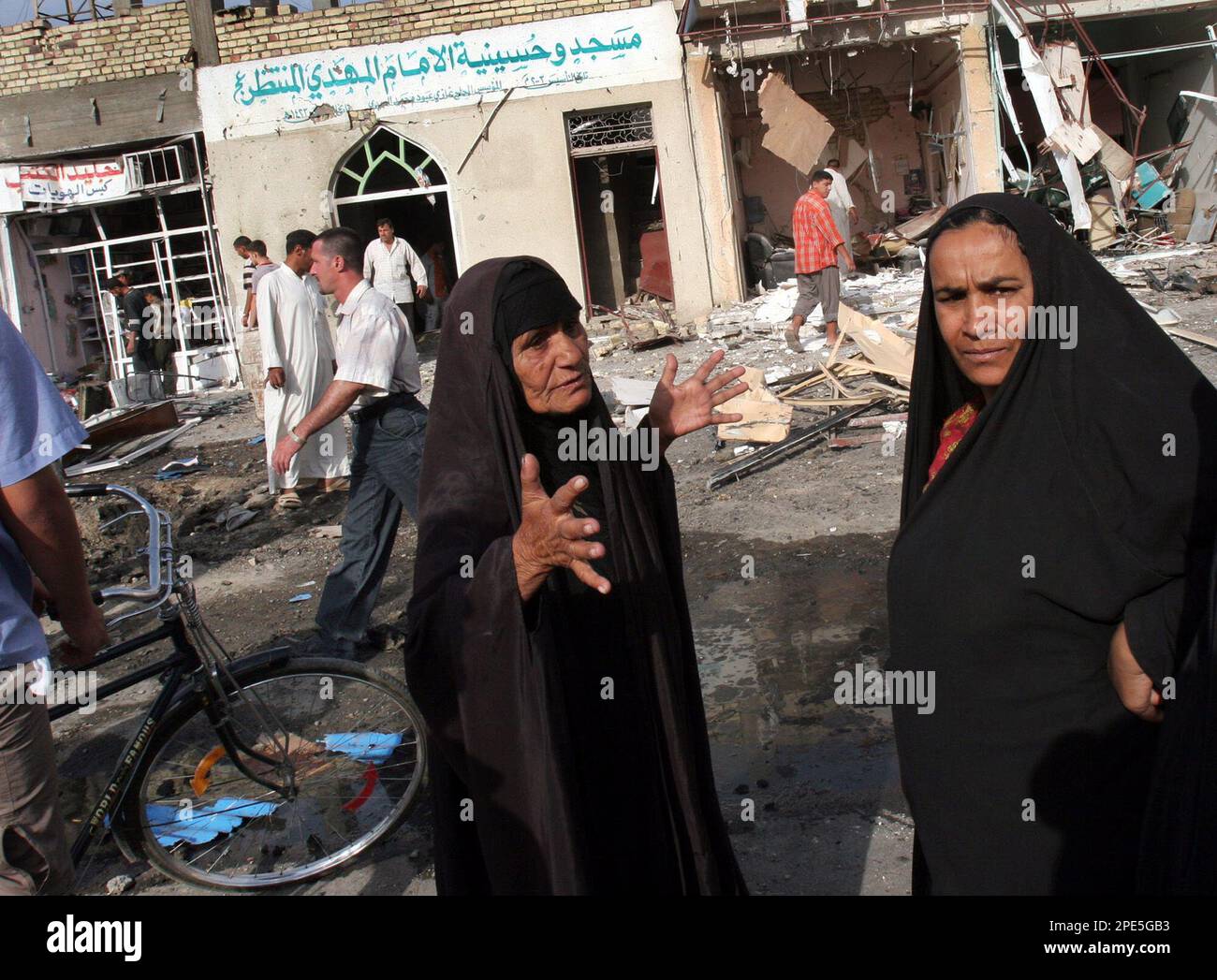 Onlookers observe the damage at the scene of a car bomb which exploded ...