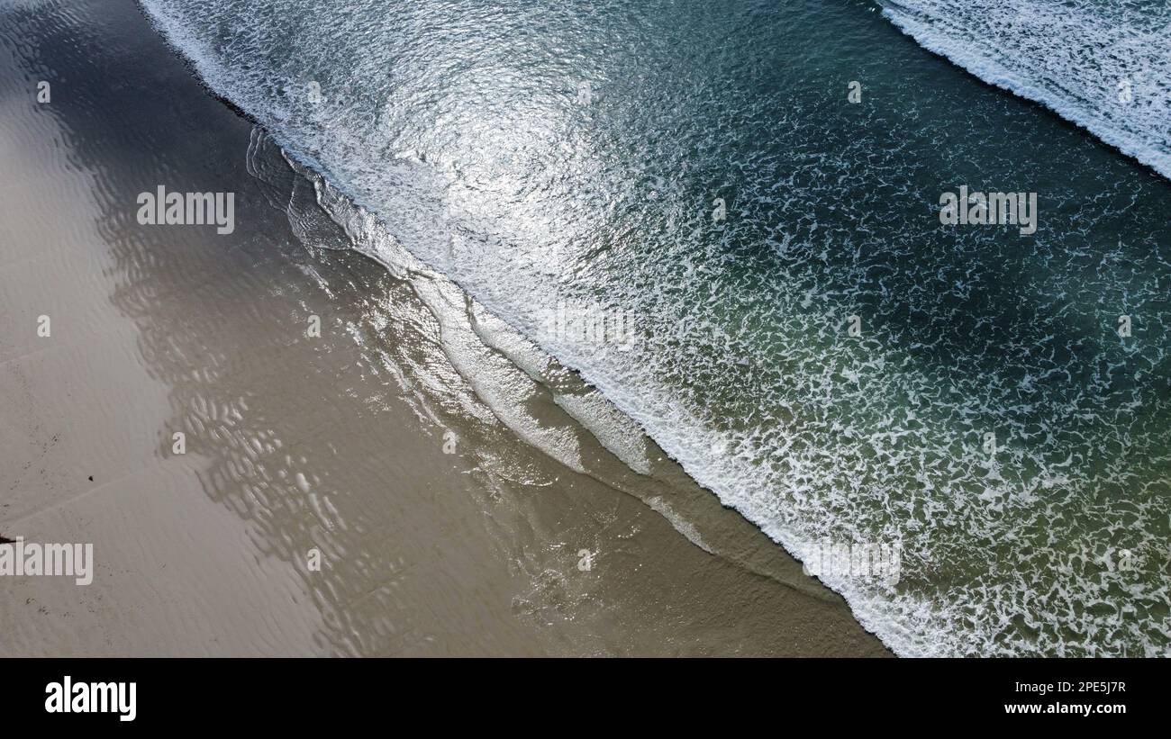 Aerial view of ocean waves rolling onto beach shoreline Stock Photo - Alamy