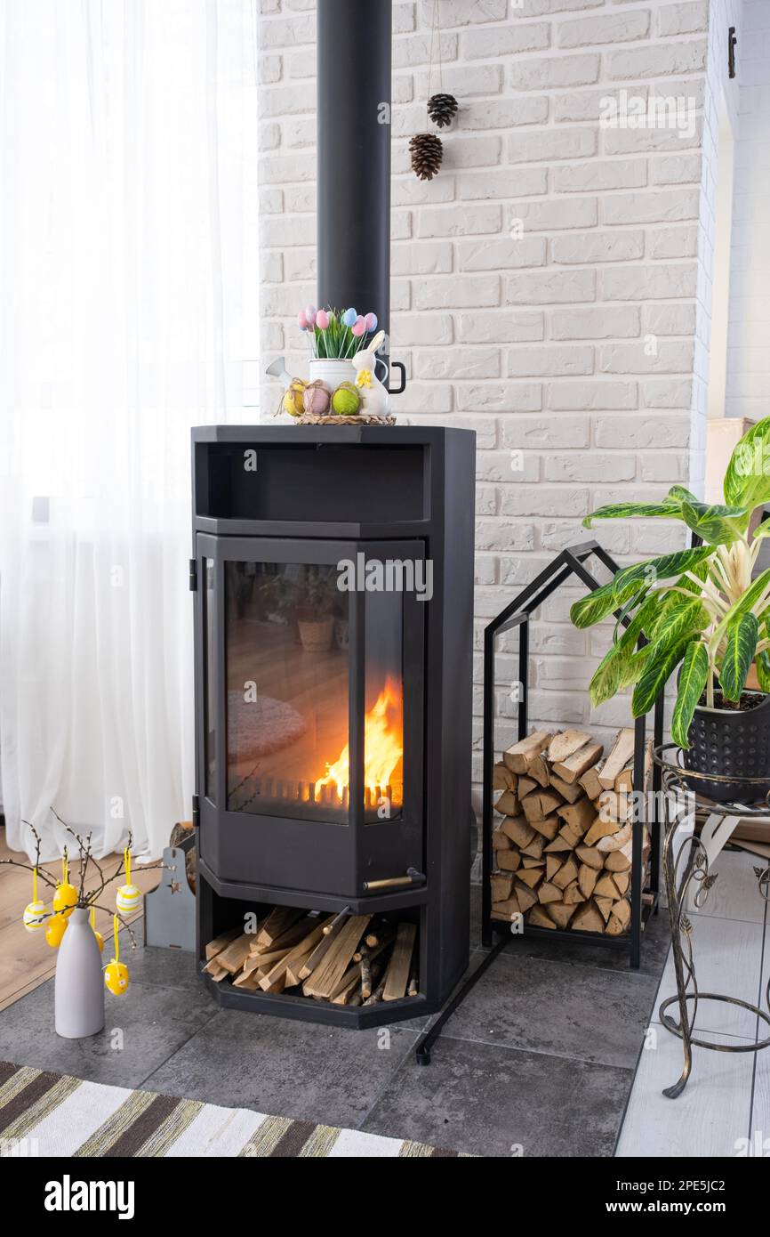 Easter decor near fireplace stove with fire and firewood. Cozy home ...