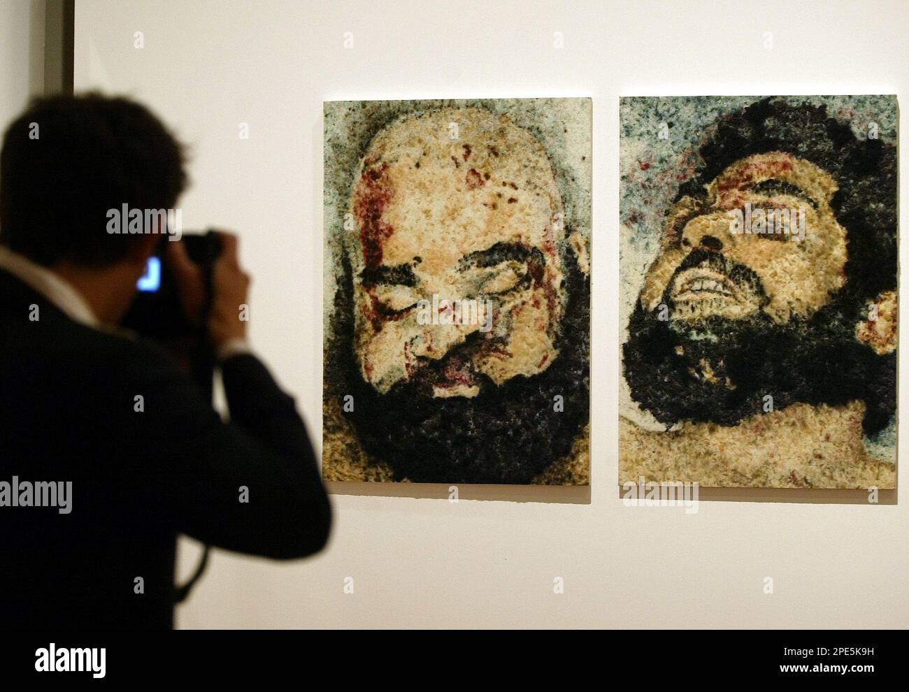 An unidentified man photographs two paintings by Israeli artist Gal ...