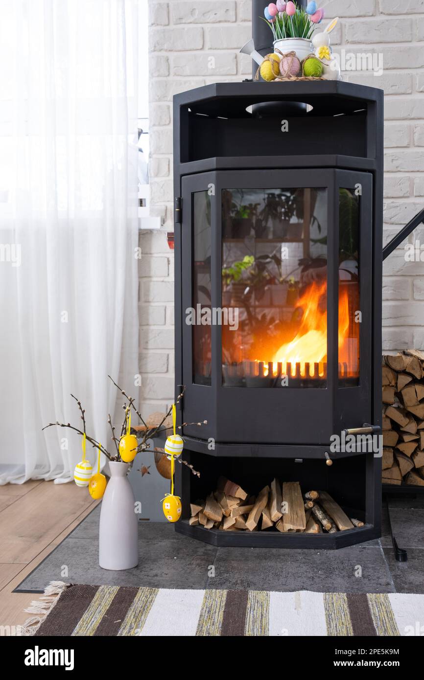 Easter decor near fireplace stove with fire and firewood. Cozy home ...